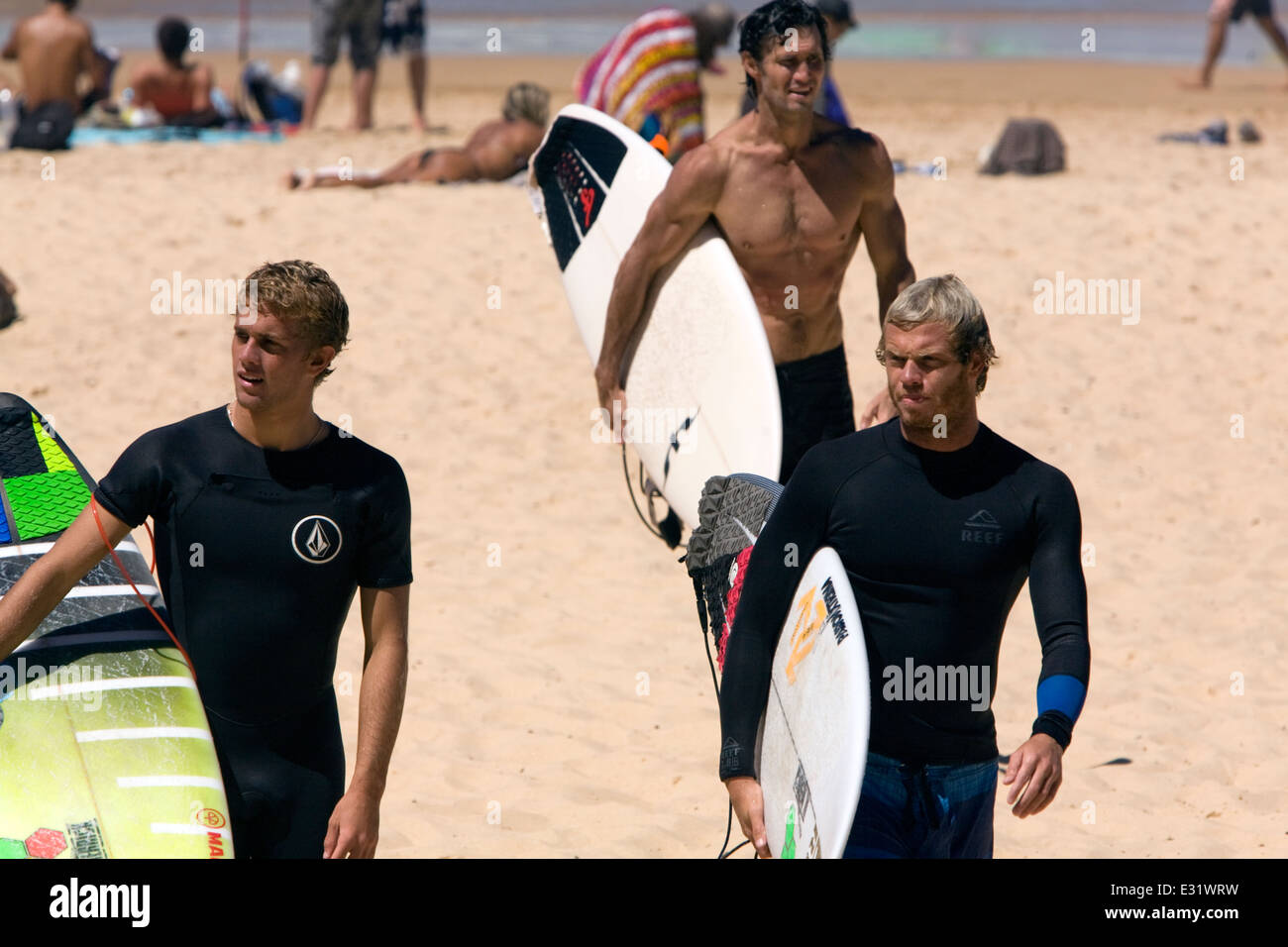 three young australian men walking across manly beach with their ...