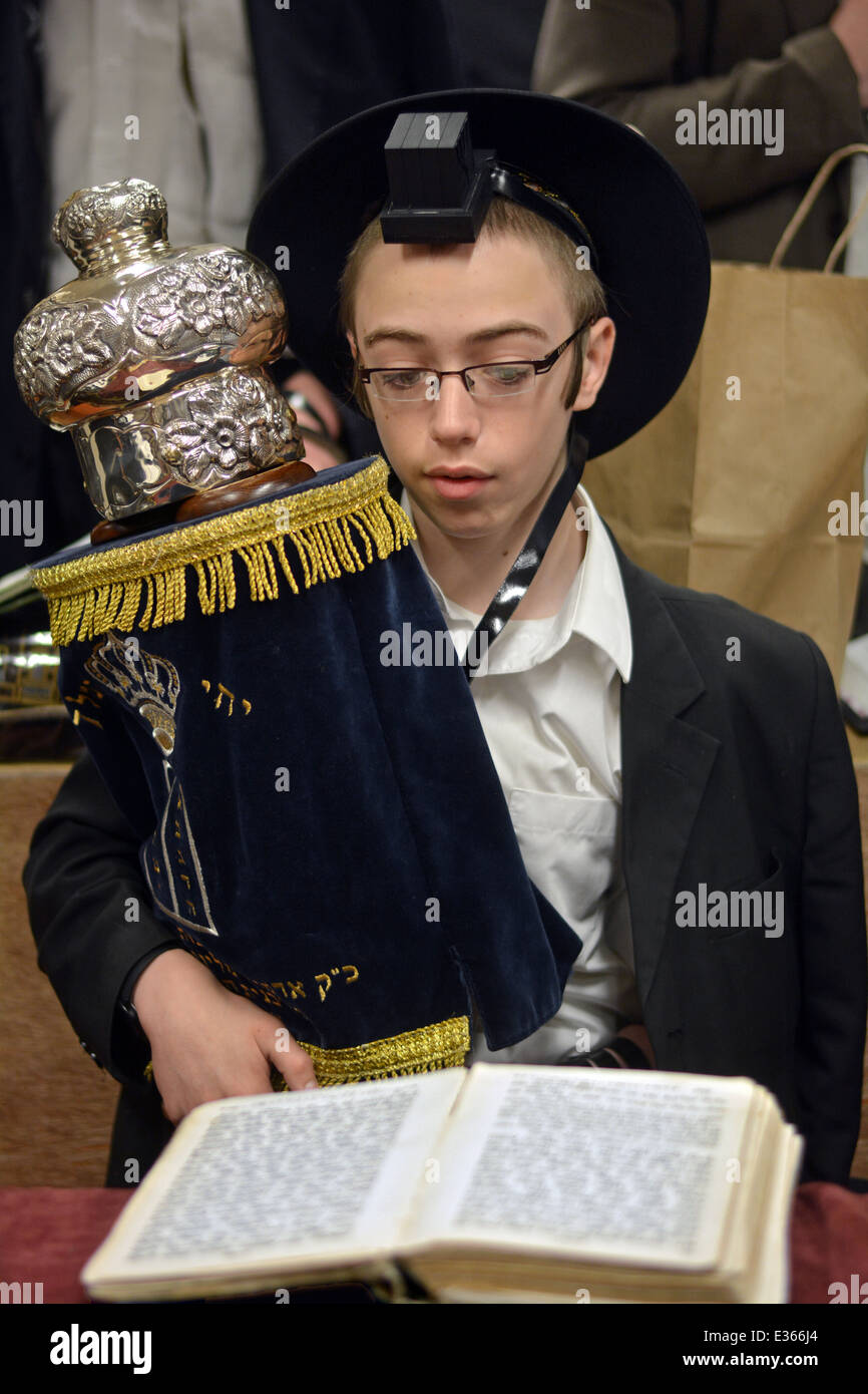 Young worshiper holding a Torah during weekday morning prayers at ...