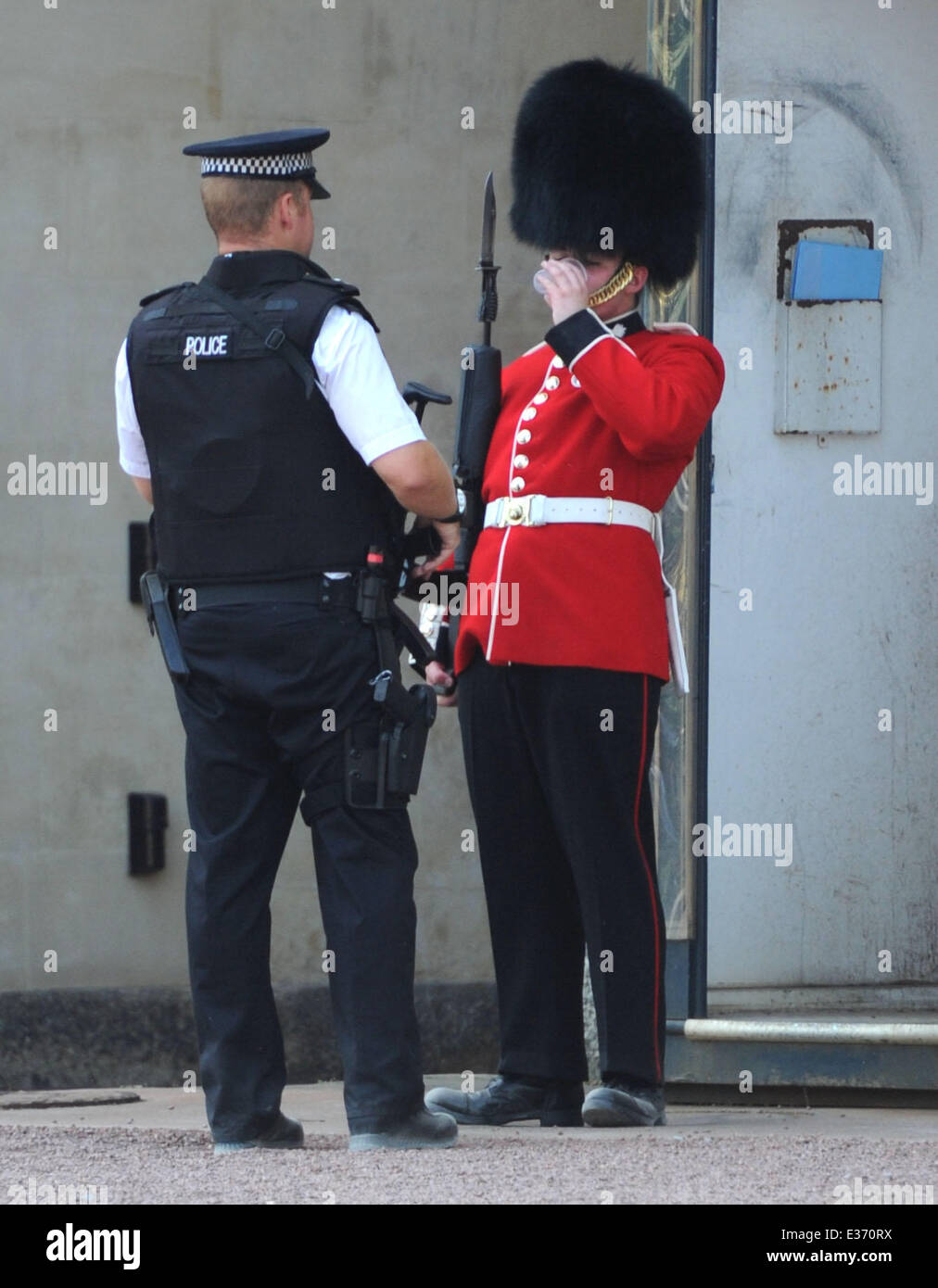 A policeman gives a Royal Guard some water as he feels the heat from ...