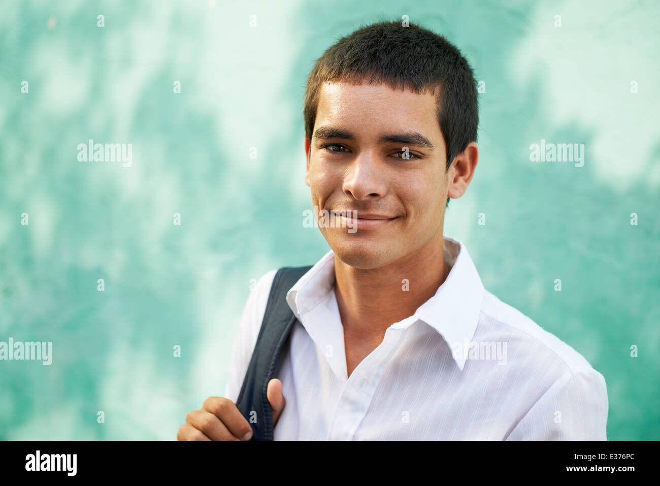 Portrait of young hispanic male student holding bag and smiling at ...