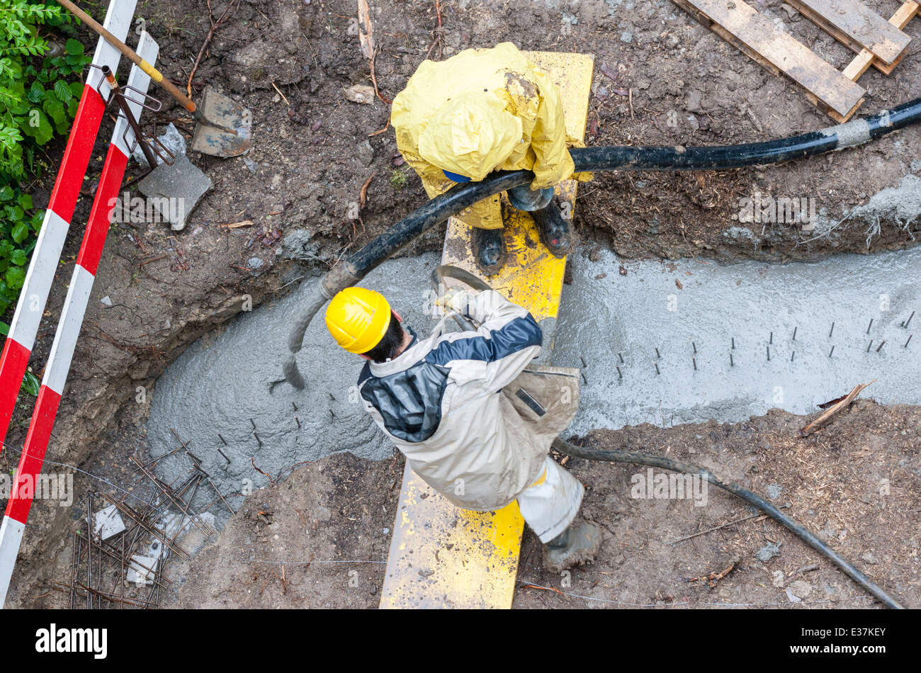 Construction workers pour concrete into a ditch. Rainy weather. Bird's ...
