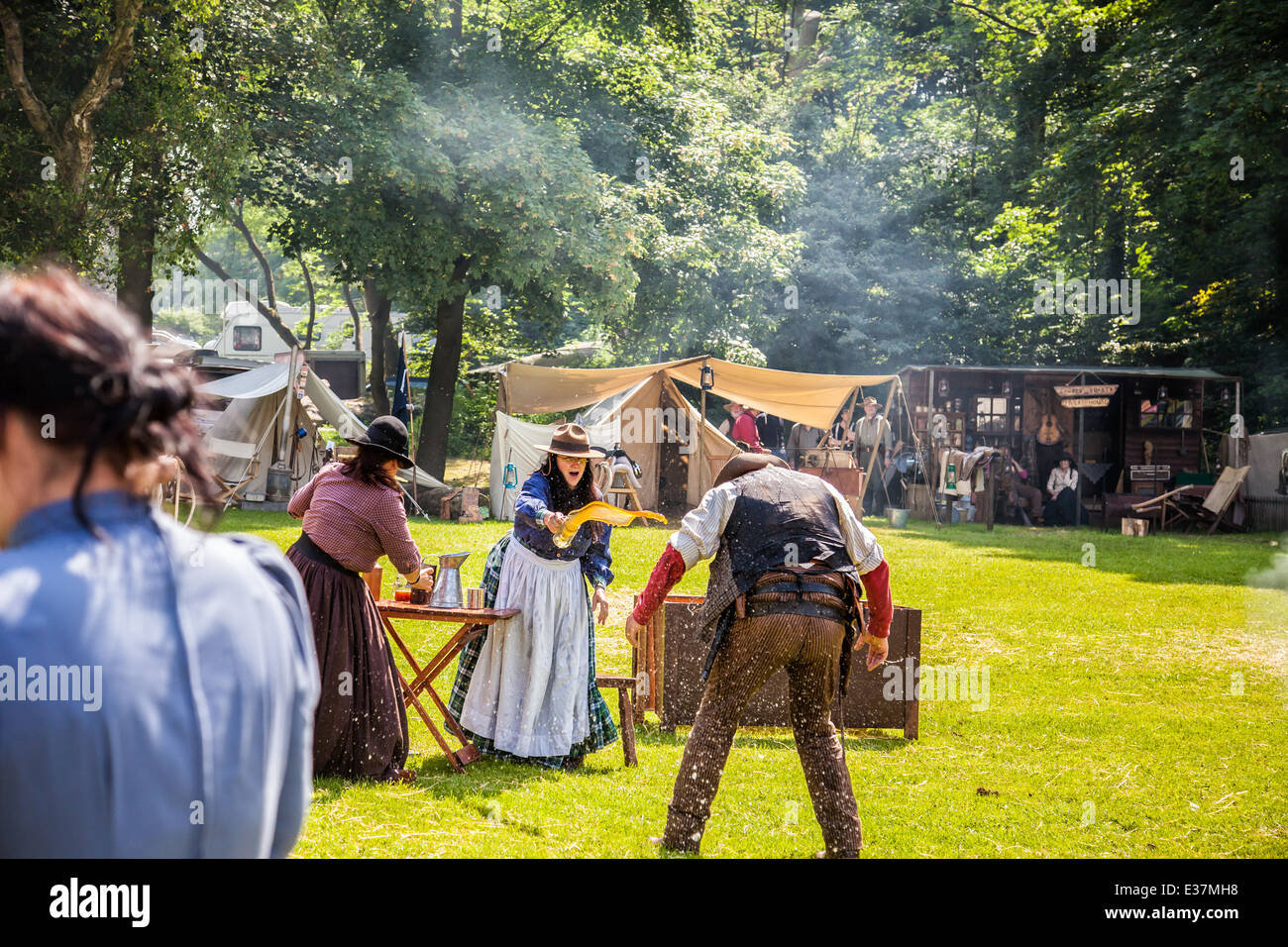 People dressed in traditional western cowboy clothes acting out a fight ...