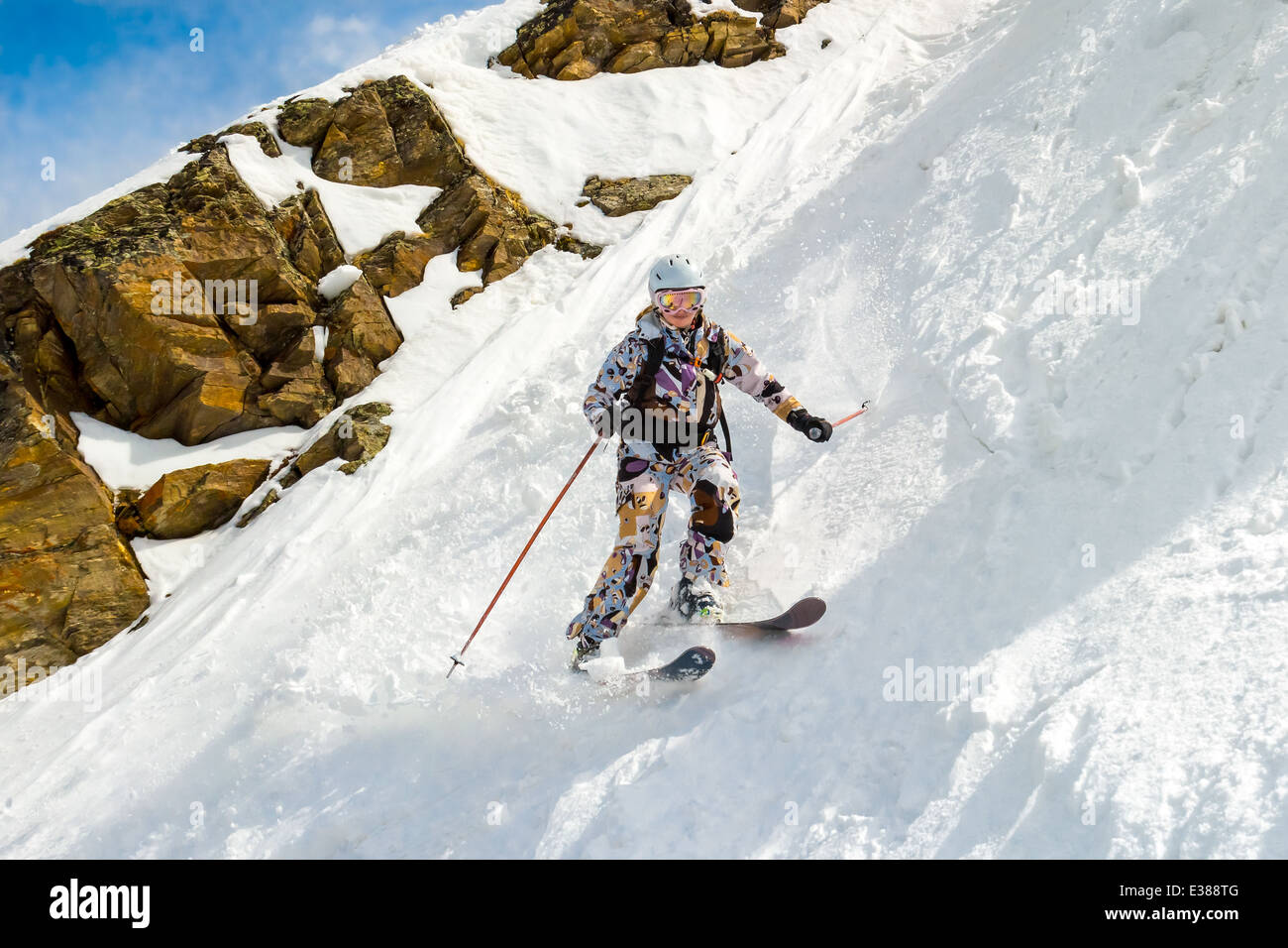 Female skier on a very steep off-piste in the background of rocks. In ...