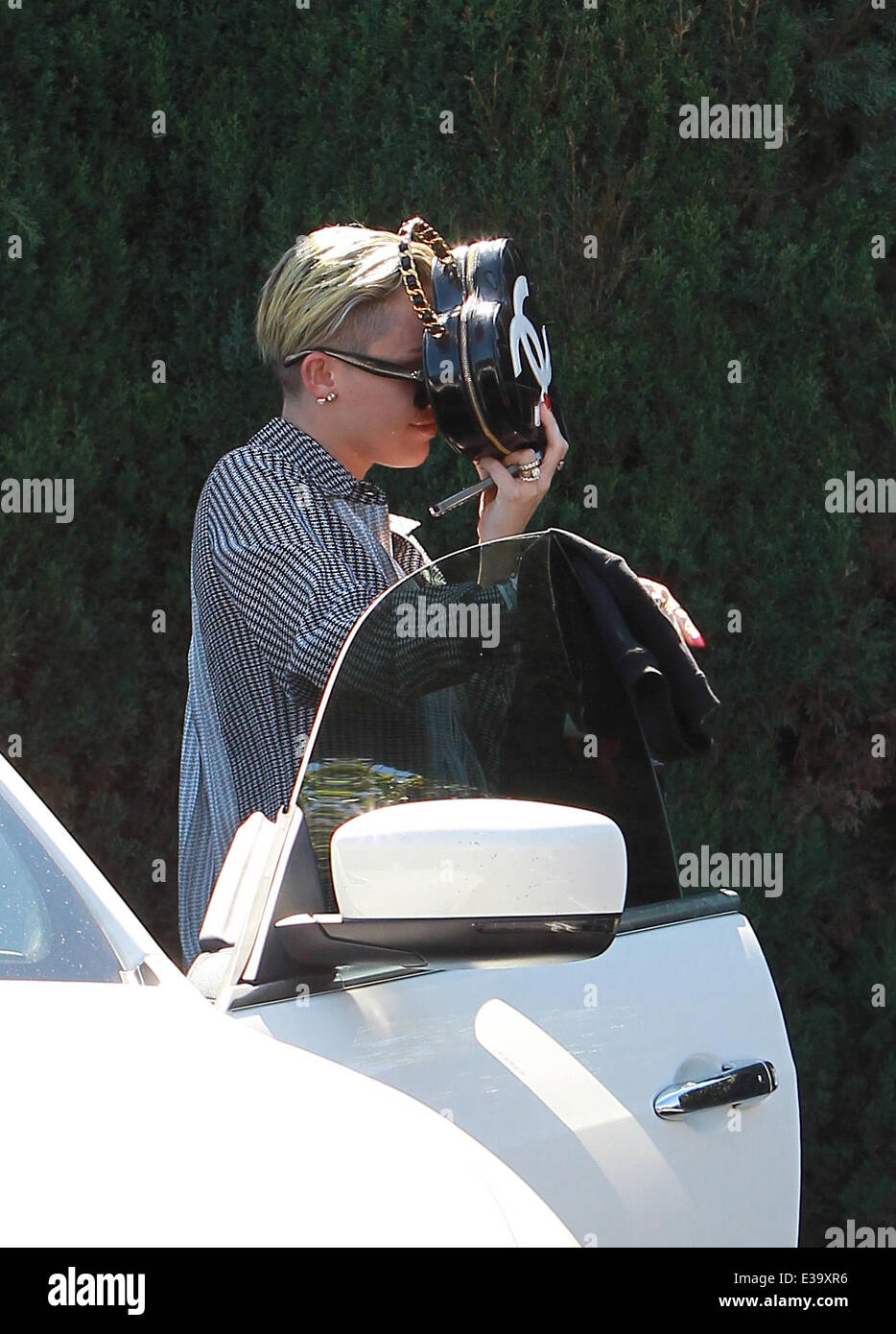 Miley Cyrus hides her face with a heart shaped Chanel handbag as she ...