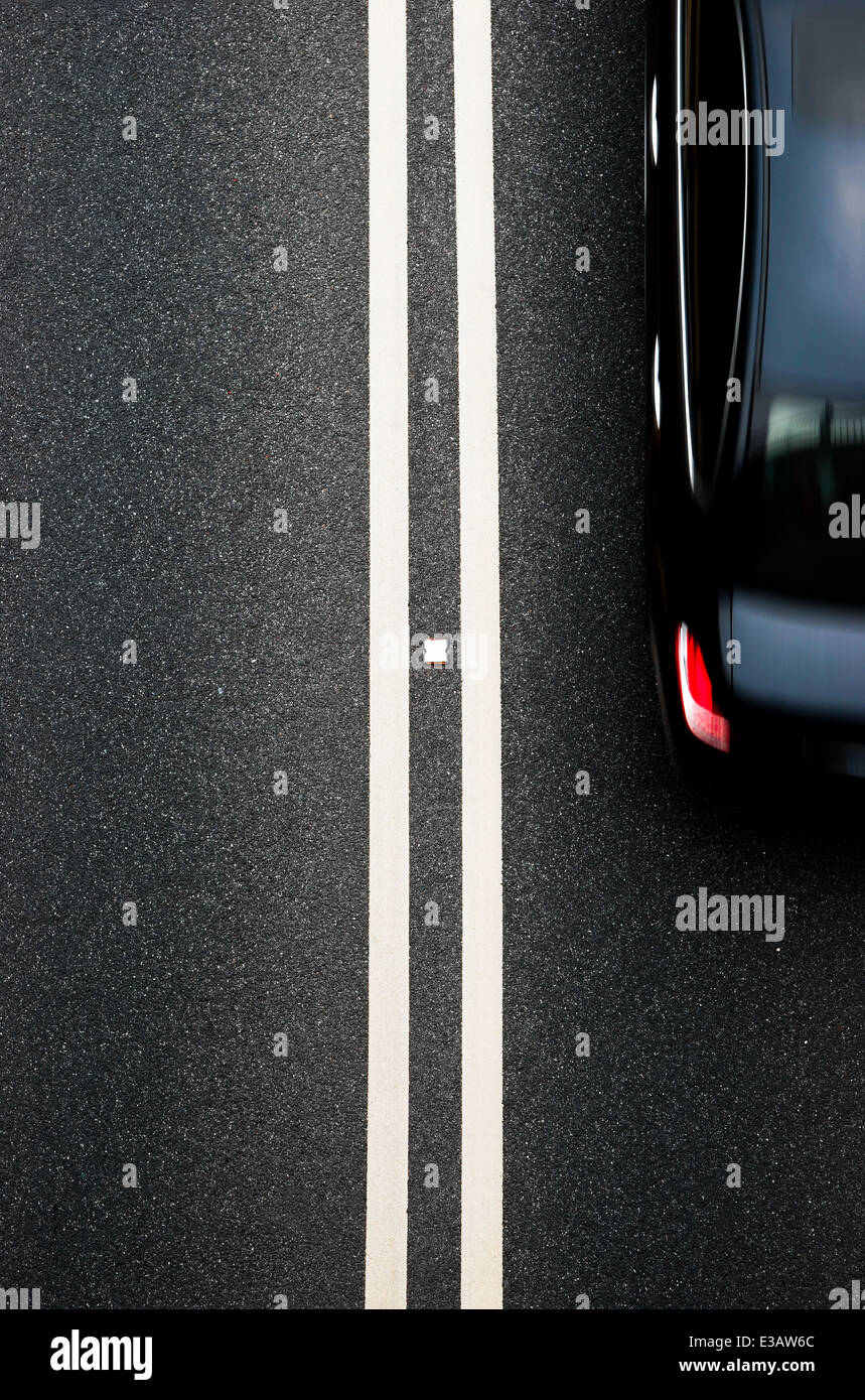 double white lines divider on blacktop with a car passing Stock Photo ...