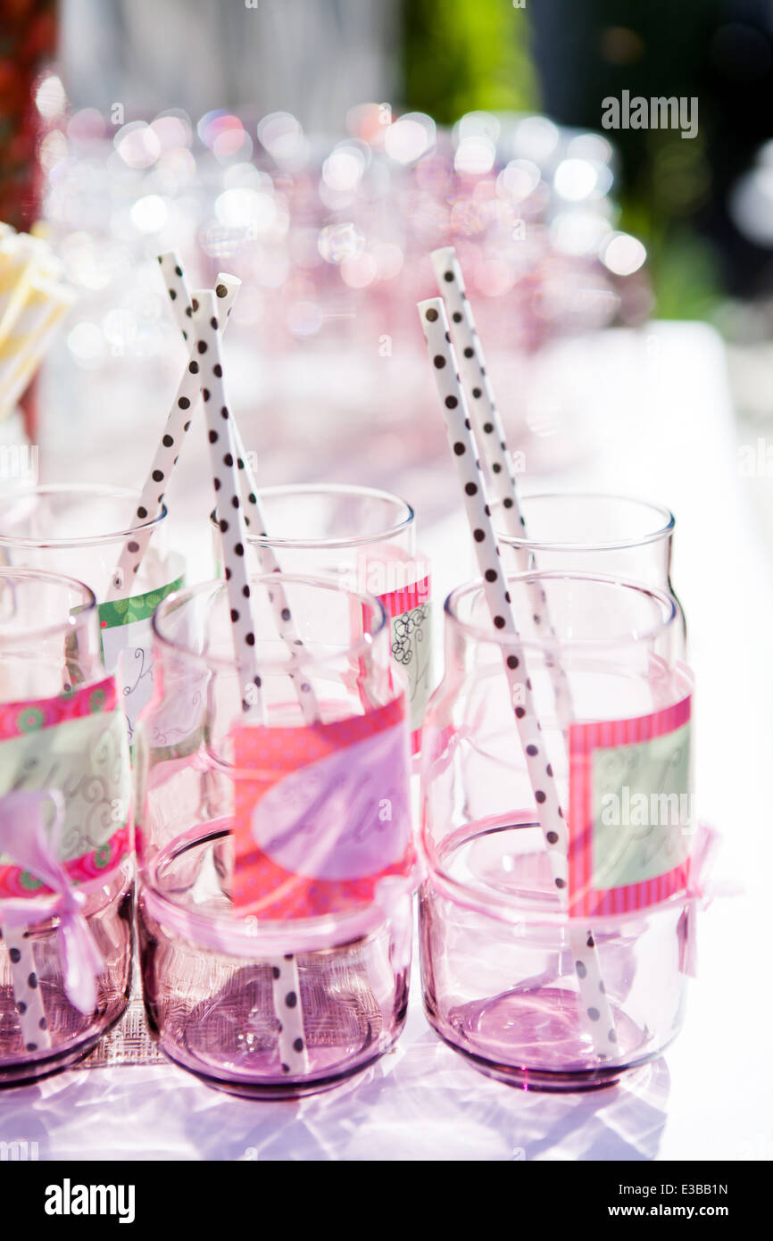 Closeup of decorative pink colored party glasses with straws and labels ...