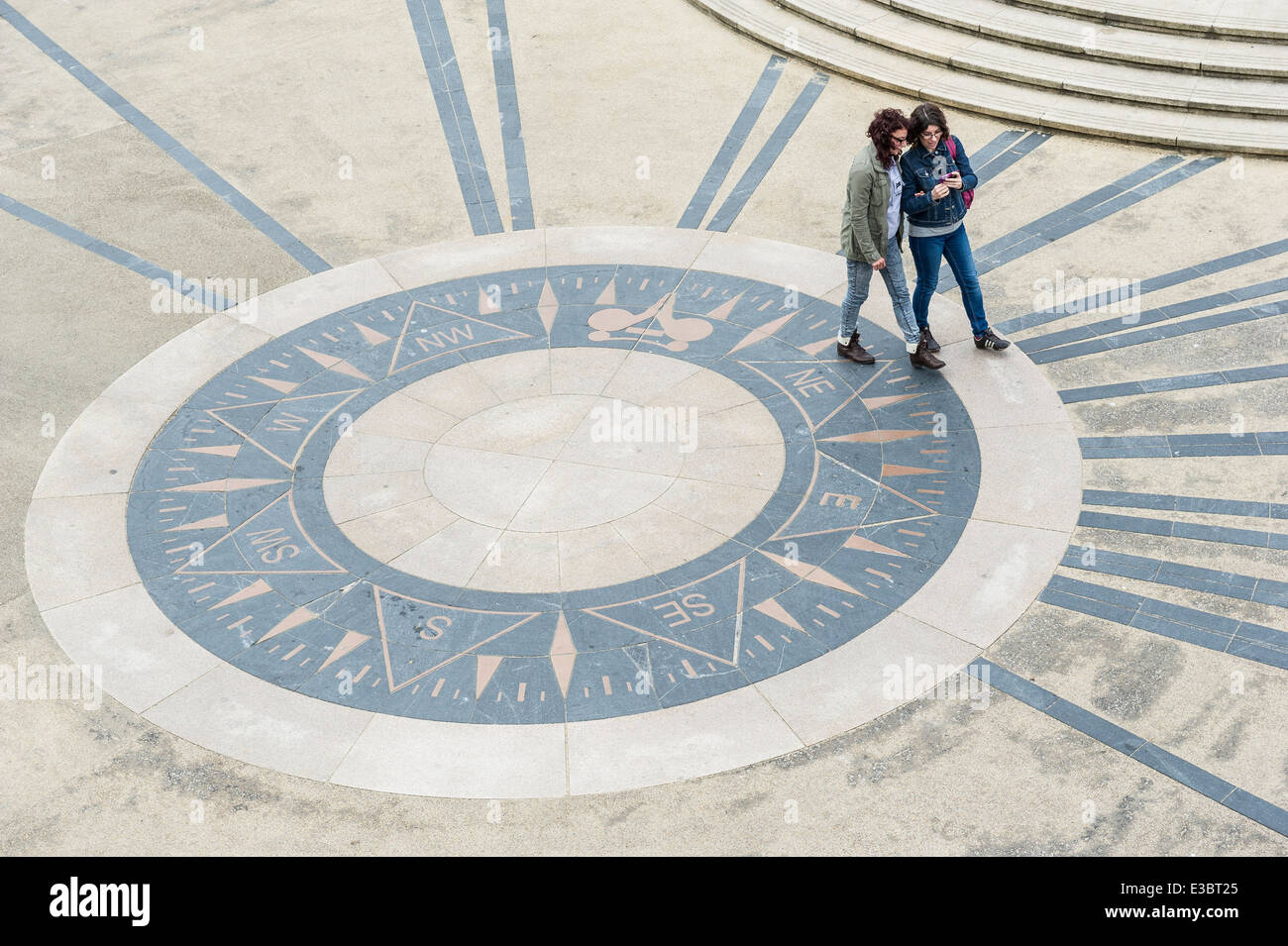 Two girls walking over a large stylised granite compass Stock Photo - Alamy