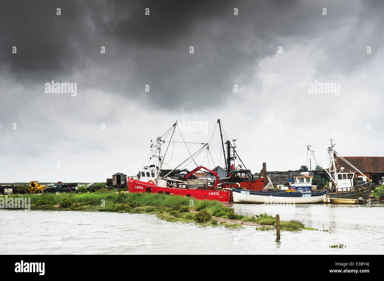 Rain clouds gathering over fishing and crab boats moored at Brancaster ...