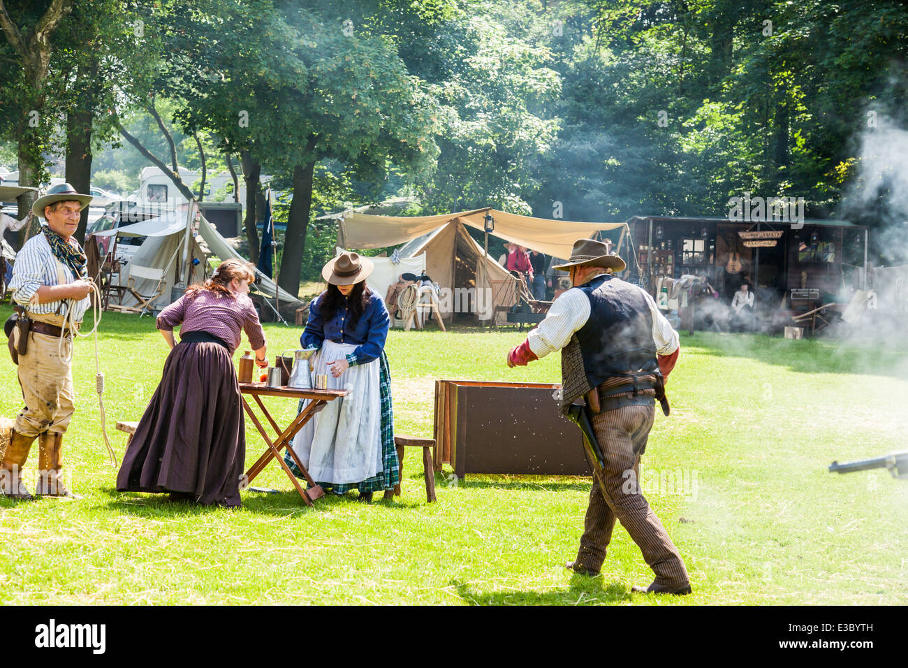 People dressed in traditional western cowboy clothes acting out a fight ...