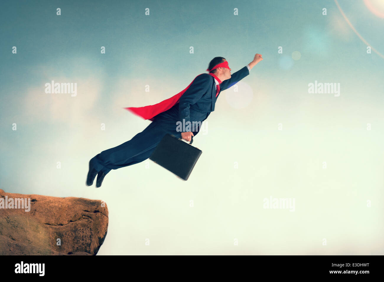 superhero businessman taking off to flight from a cliff ledge wearing a ...