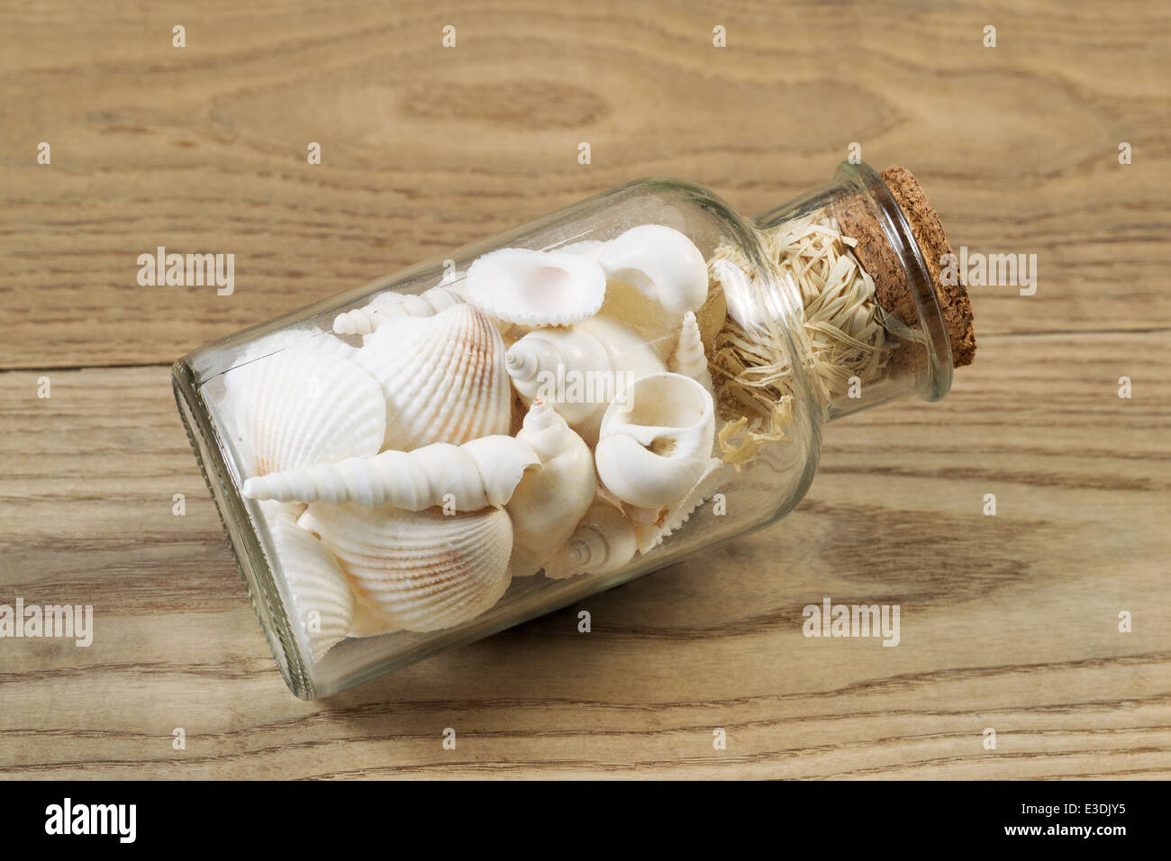Horizontal view of a glass bottle filled with sea shells on rustic wood ...