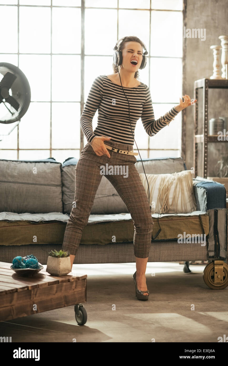 Full length portrait of young woman listening rock music in headphones ...