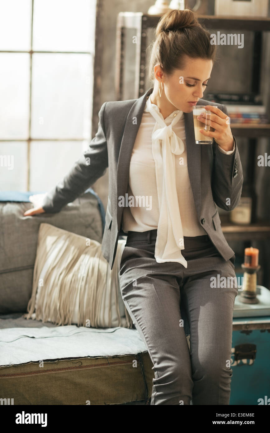 Business woman with coffee latte sitting on divan in loft apartment ...