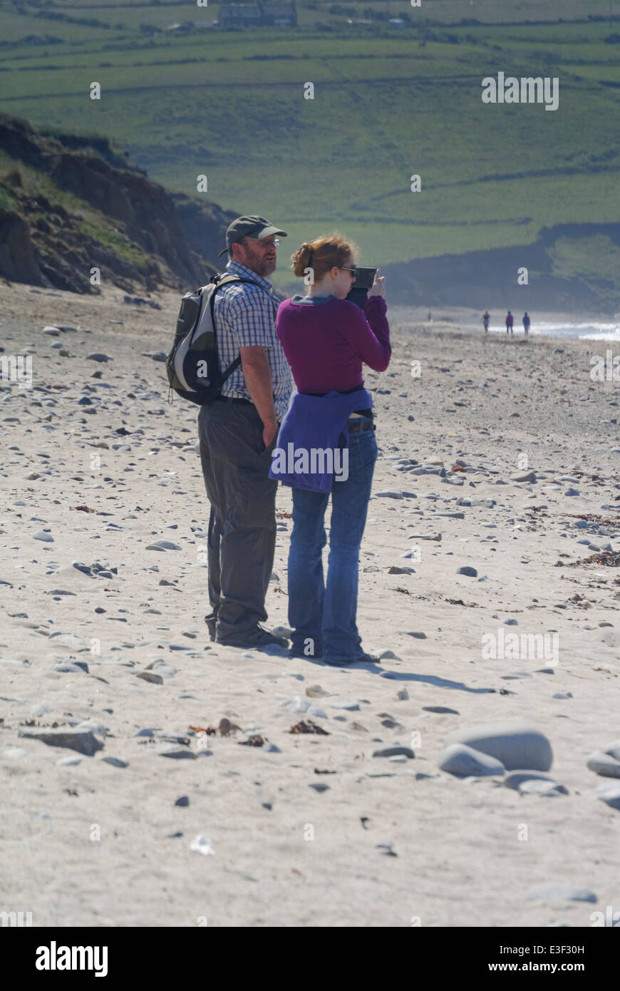 A couple arrive at the beach and watch the surfers Stock Photo - Alamy