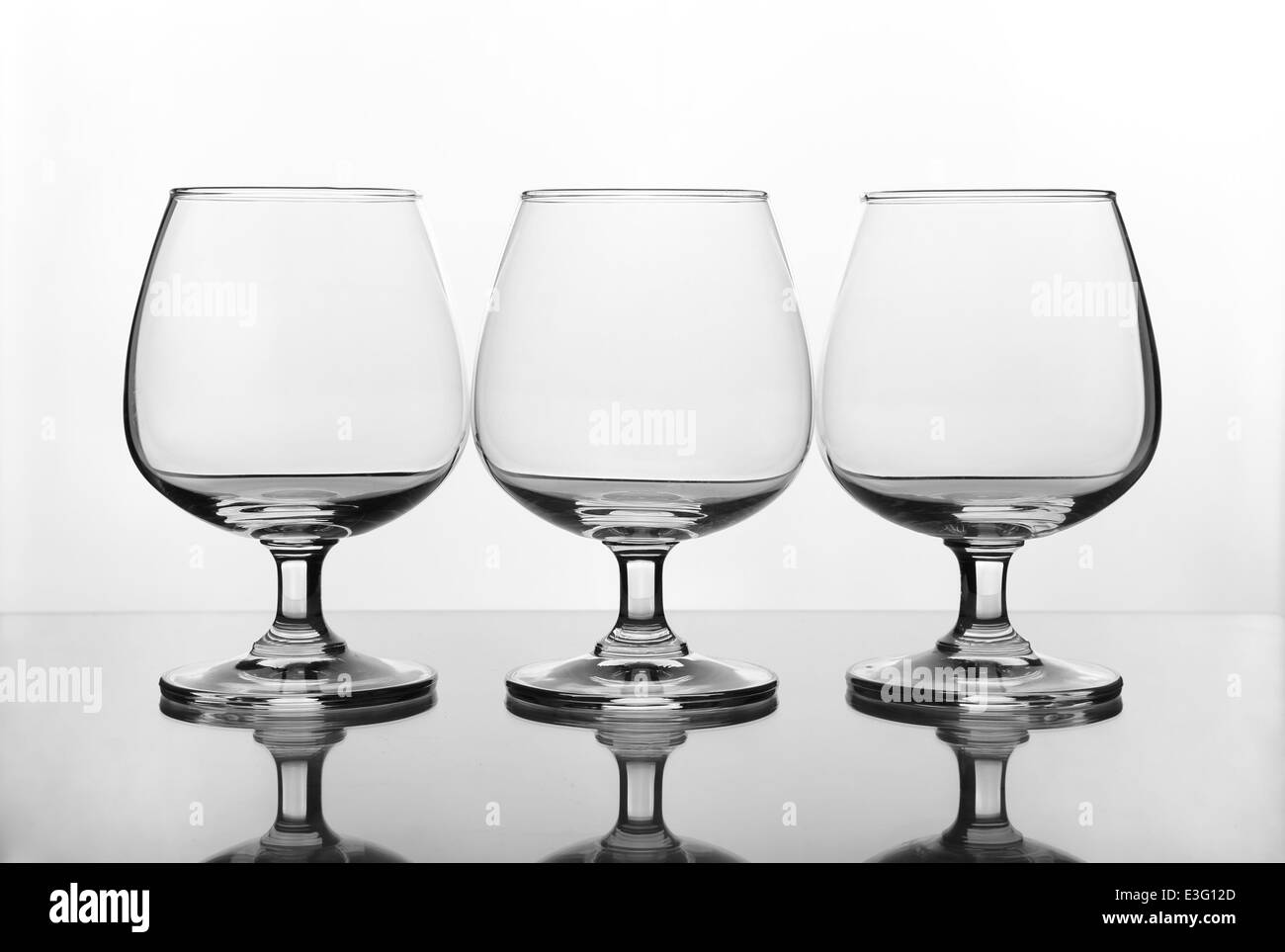 three empty wine glass on glass table (gray scale Stock Photo - Alamy