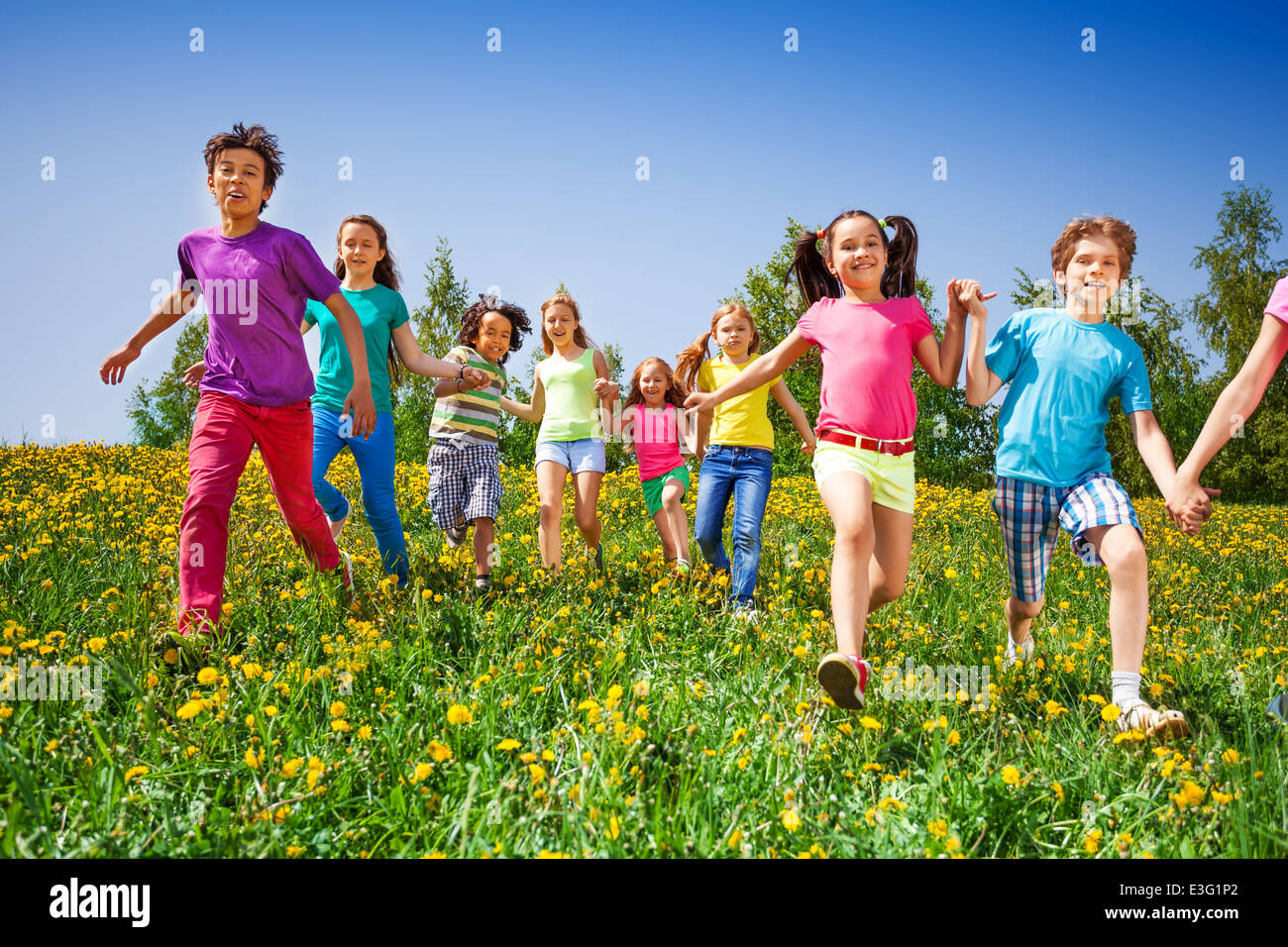 Happy kids run and hold hands in green meadow Stock Photo - Alamy