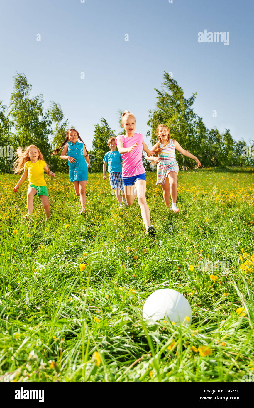 Happy children playing football in green field Stock Photo - Alamy