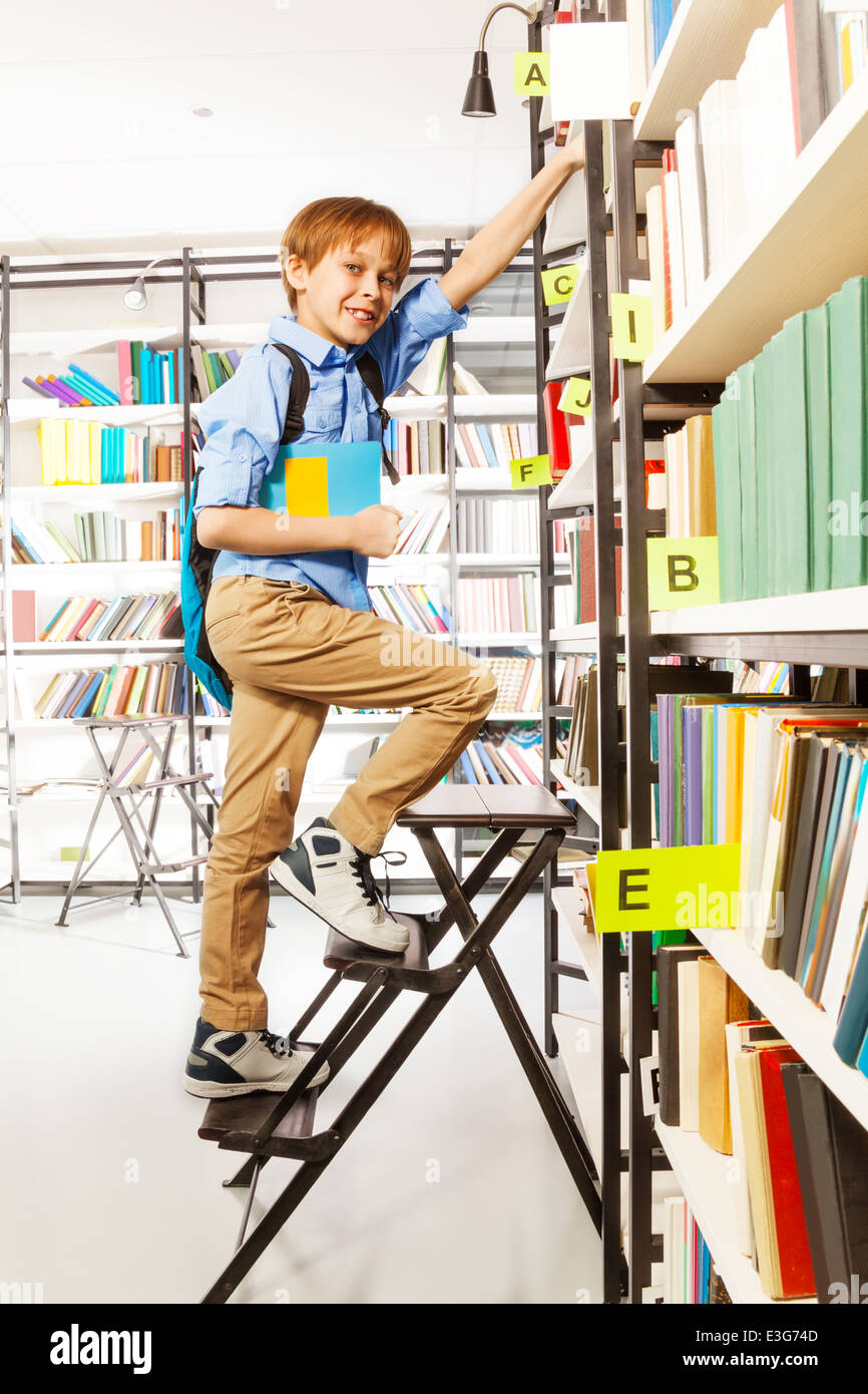 Boy climbing on step ladder in library Stock Photo - Alamy