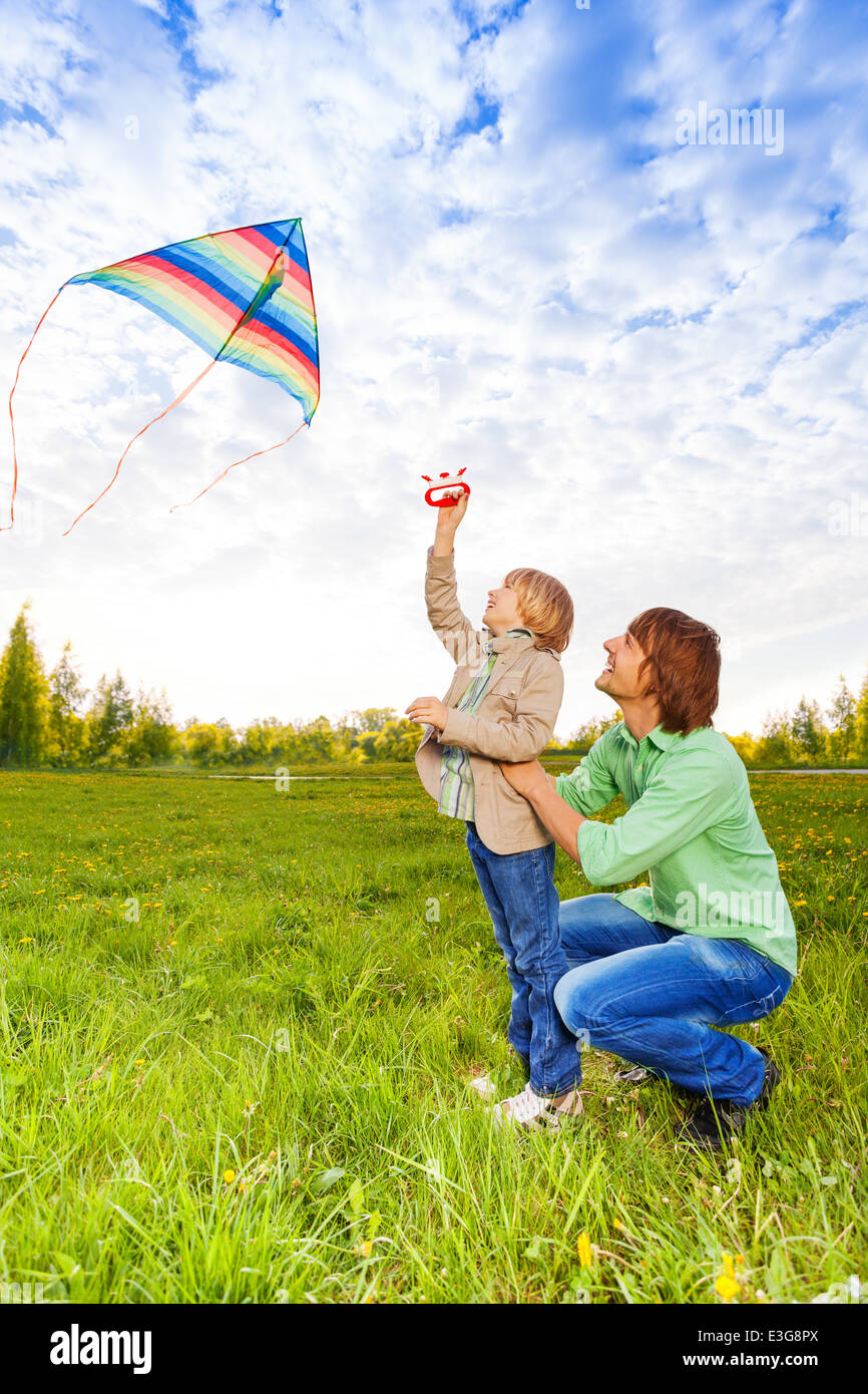 Father holds kid while watching flying kite Stock Photo - Alamy