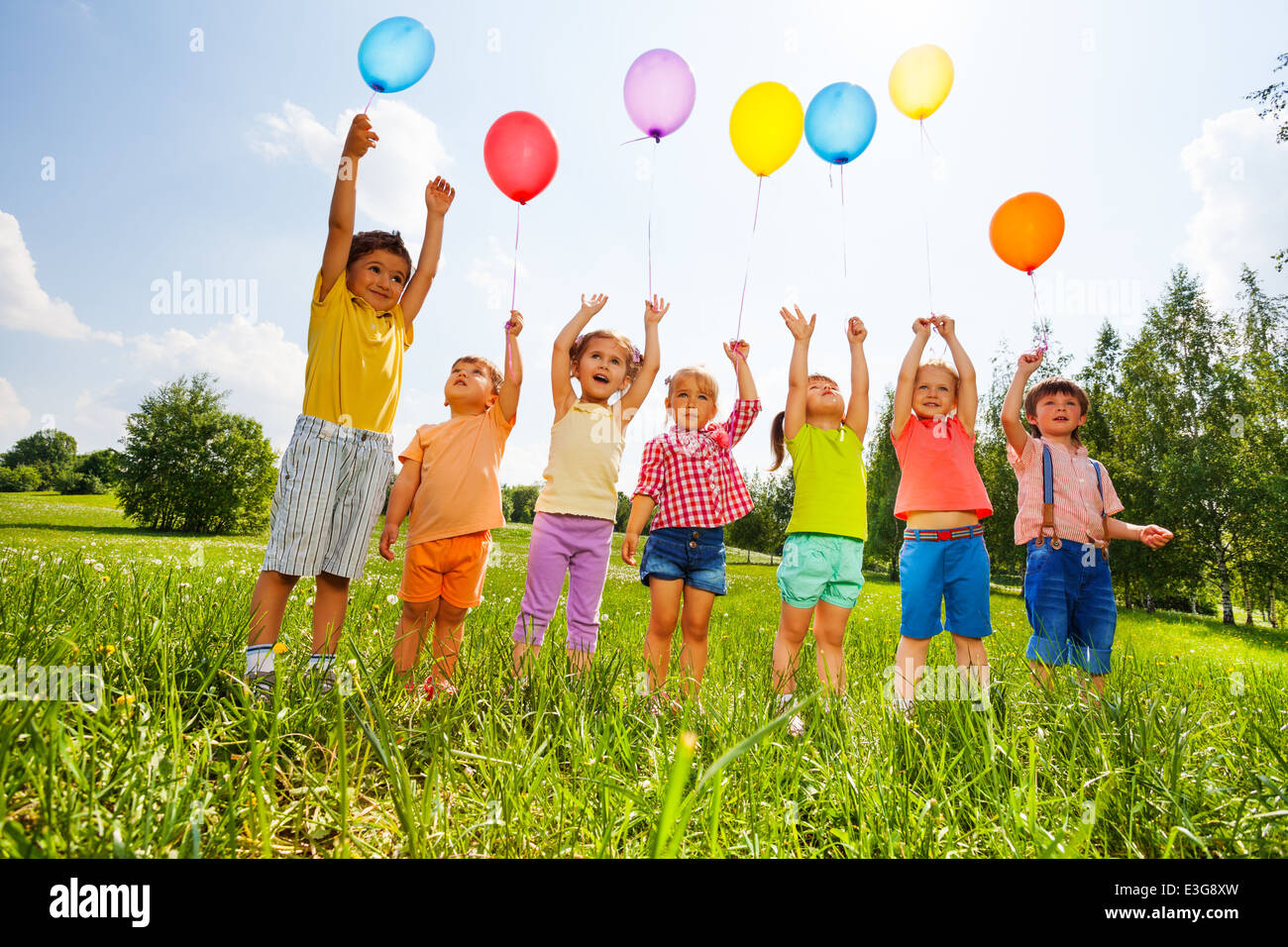 Happy kids with balloons and arms up in the sky Stock Photo - Alamy