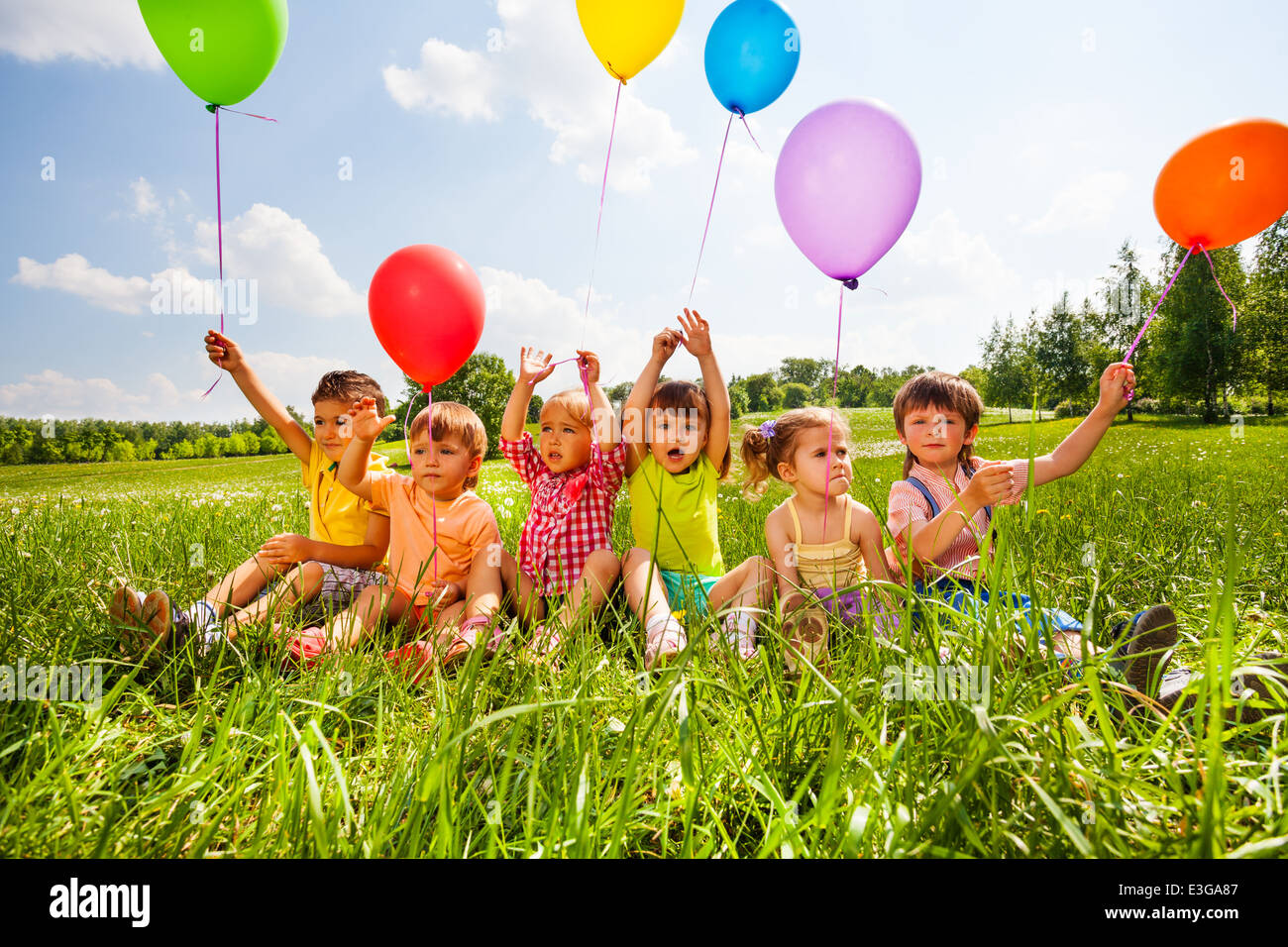 Sitting funny kids with balloons in the air Stock Photo - Alamy