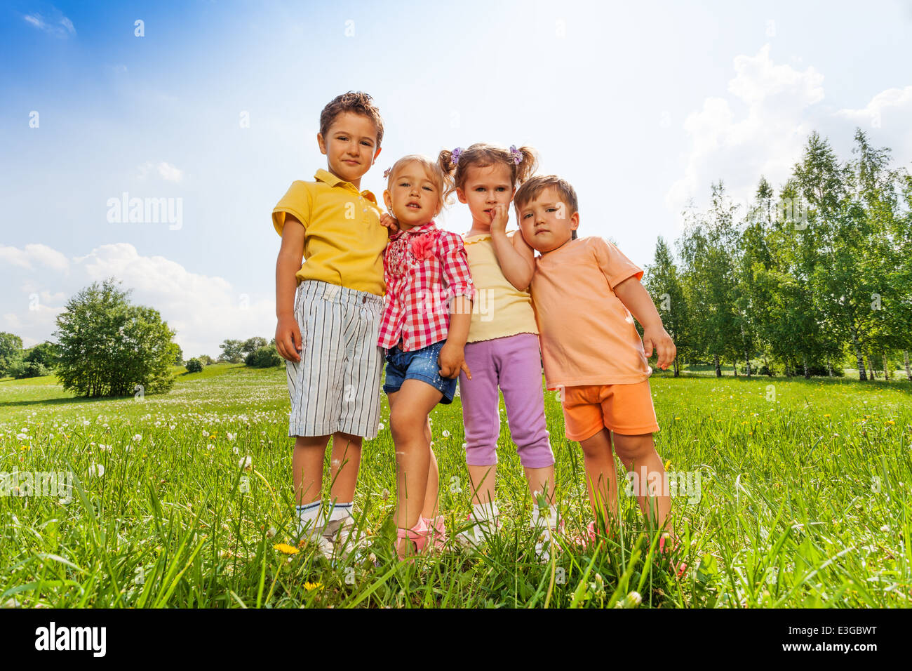 Four kids standing close to each other in meadow Stock Photo - Alamy