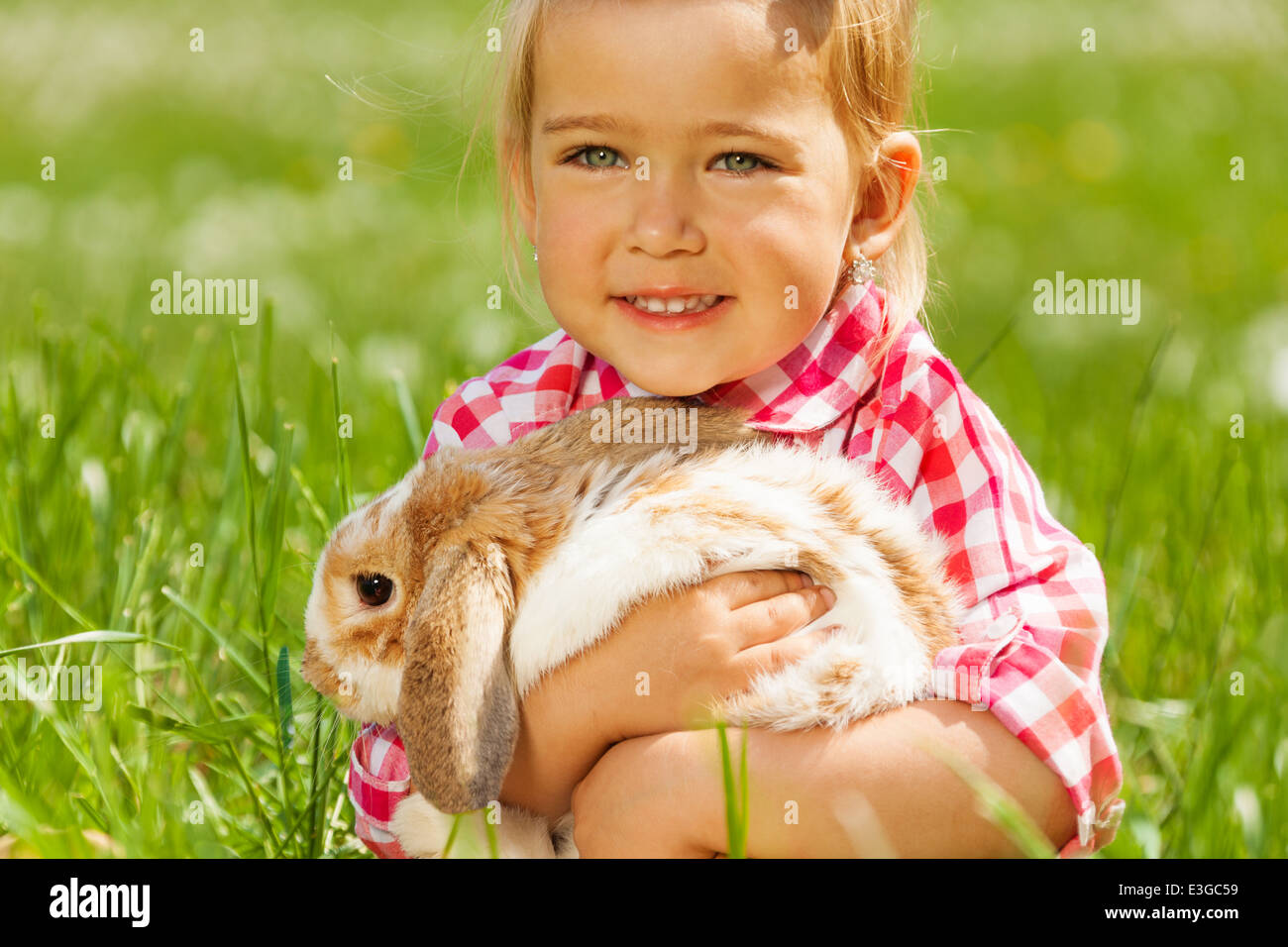 Cute girl cuddling rabbit in green field Stock Photo - Alamy