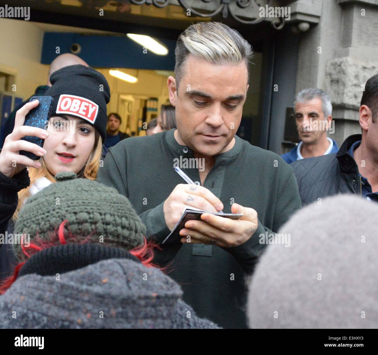 Robbie Williams signs autographs for fans as he leaves Hotel Principe ...