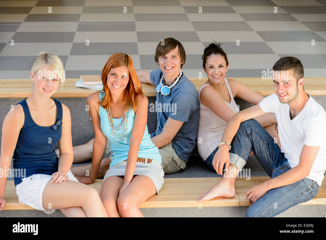 Group of college student friends sitting on bench looking camera Stock ...