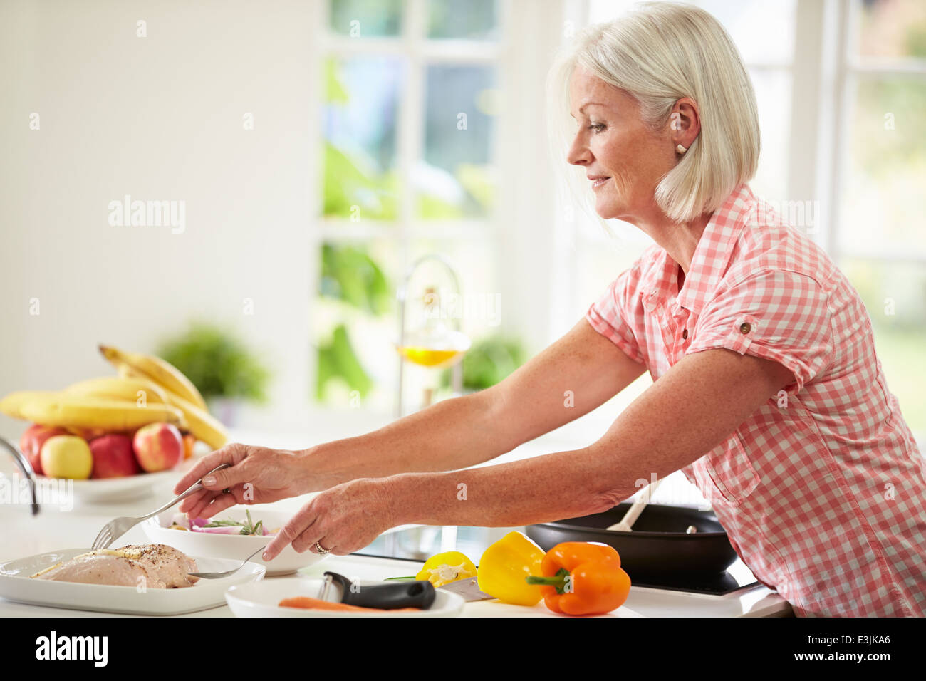 Middle Aged Woman Cooking Meal In Kitchen Stock Photo - Alamy