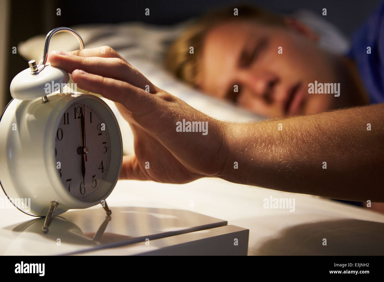 Teenage Boy Waking Up In Bed And Turning Off Alarm Clock Stock Photo ...