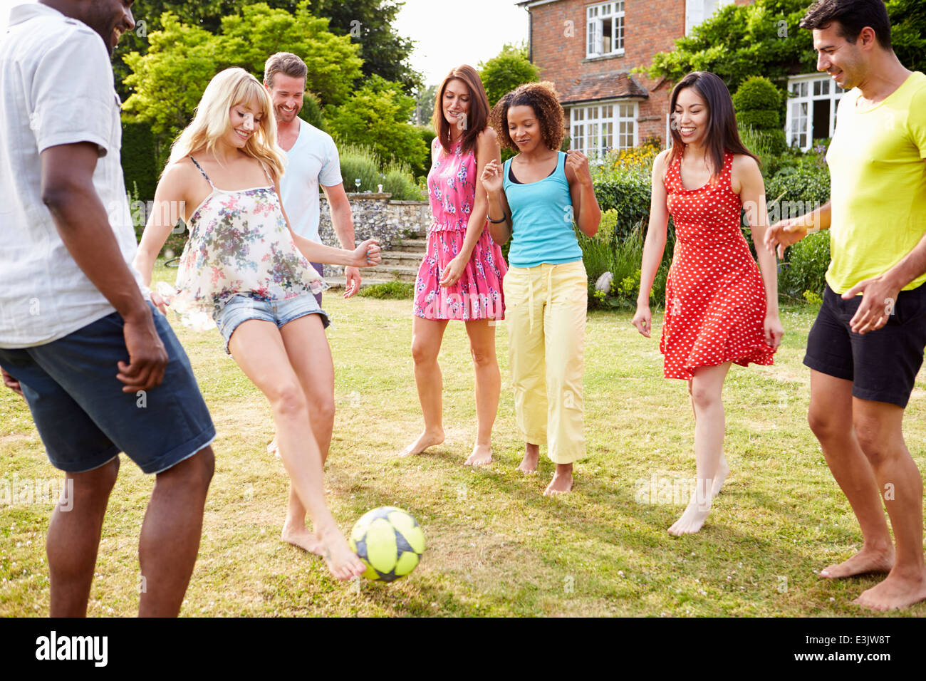 Group Of Friends Playing Football In Garden Stock Photo - Alamy