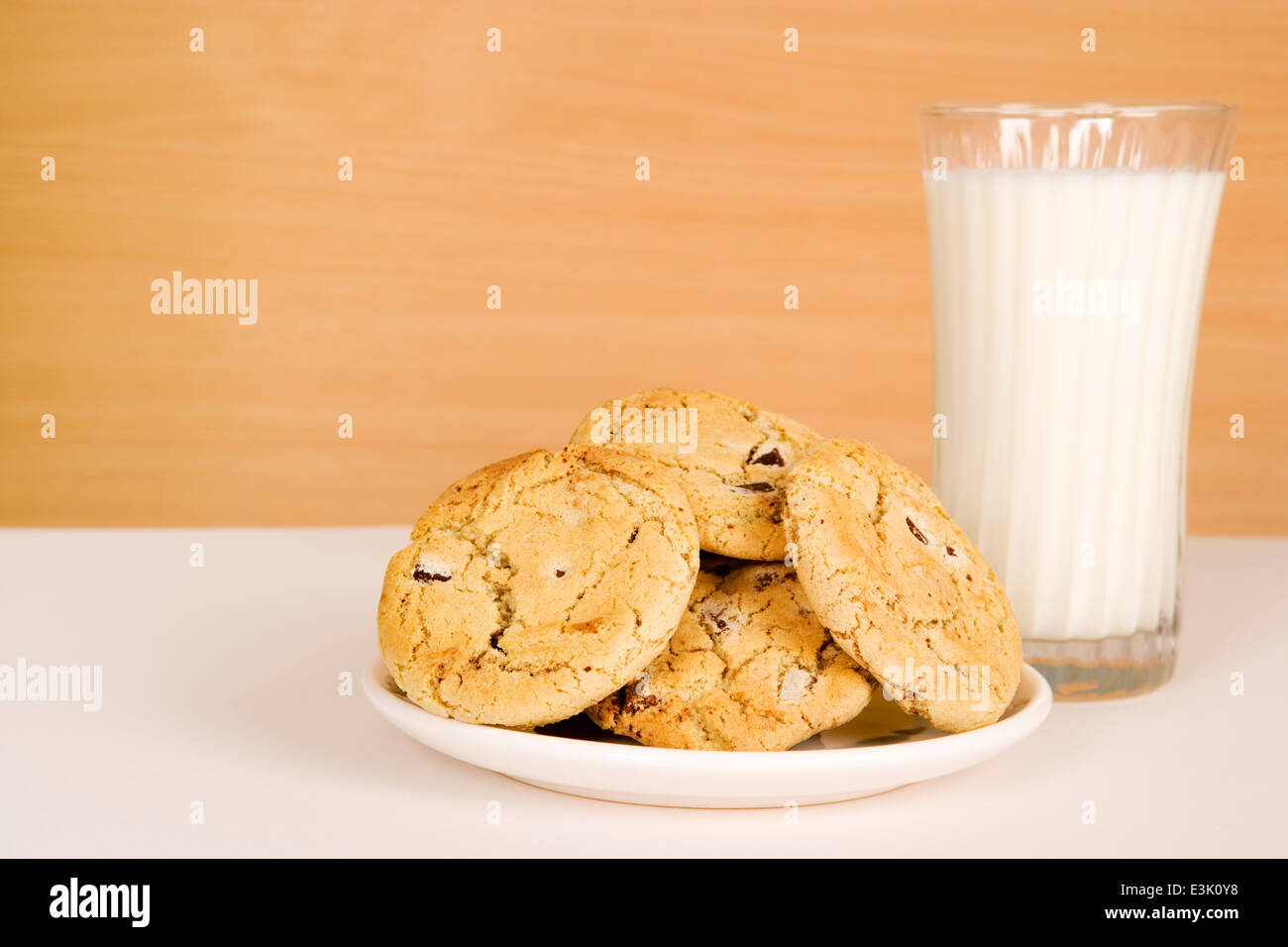 Chocolate chip cookies in saucer standing next to glass of milk Stock ...