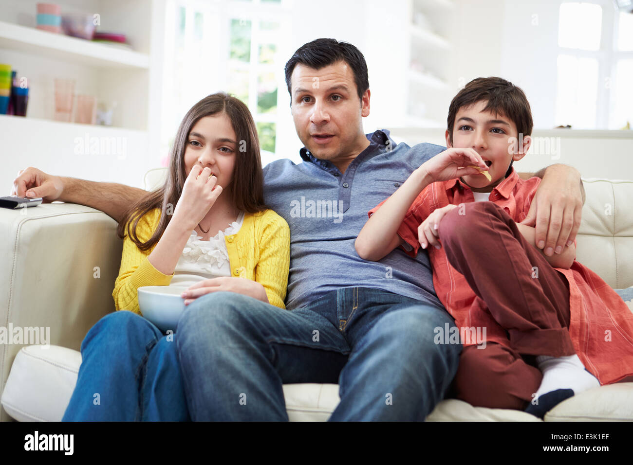 Father And Children Sitting On Sofa Watching TV Together Stock Photo ...