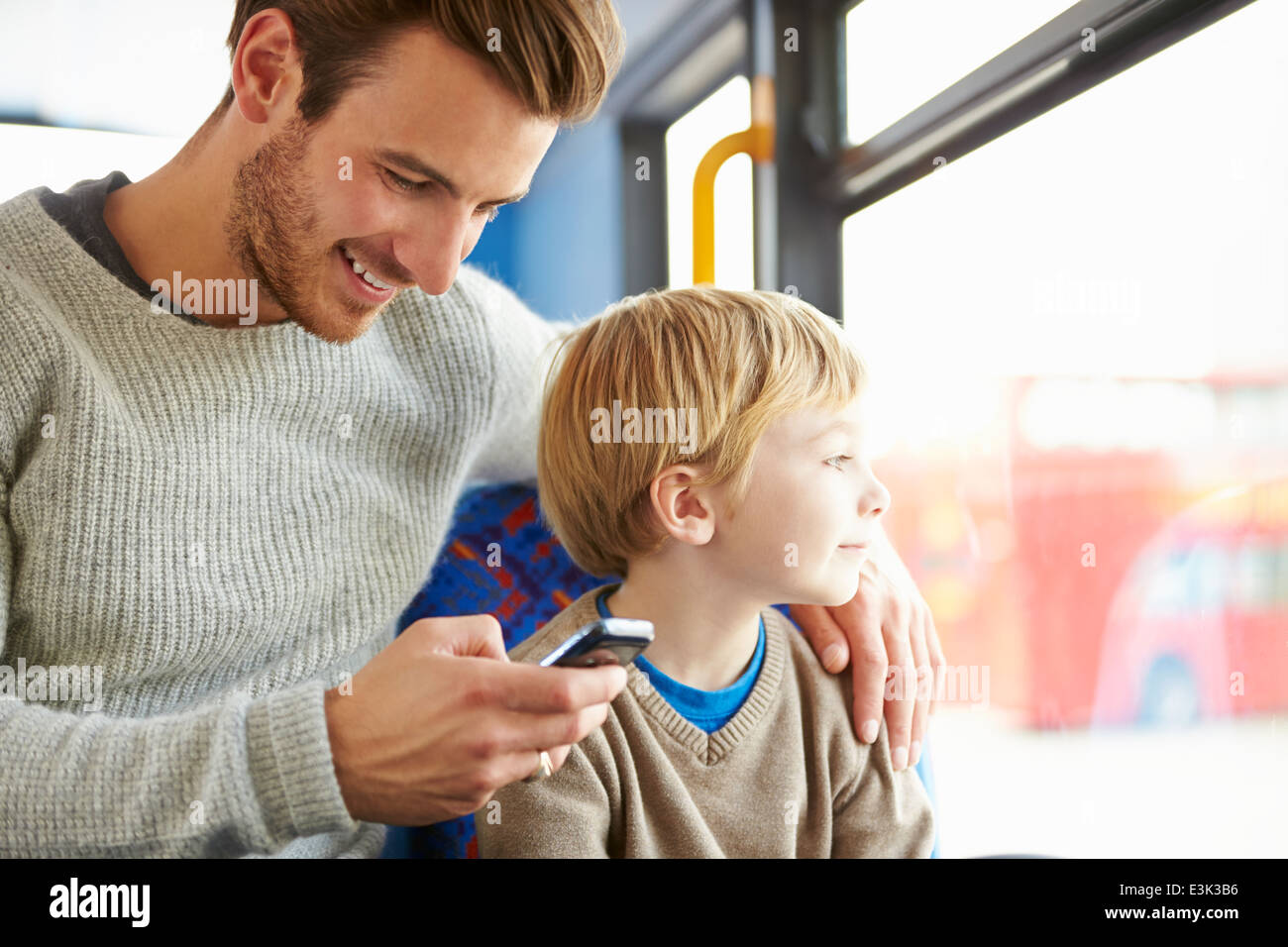 Father Using Mobile Phone On Bus Journey With Son Stock Photo - Alamy