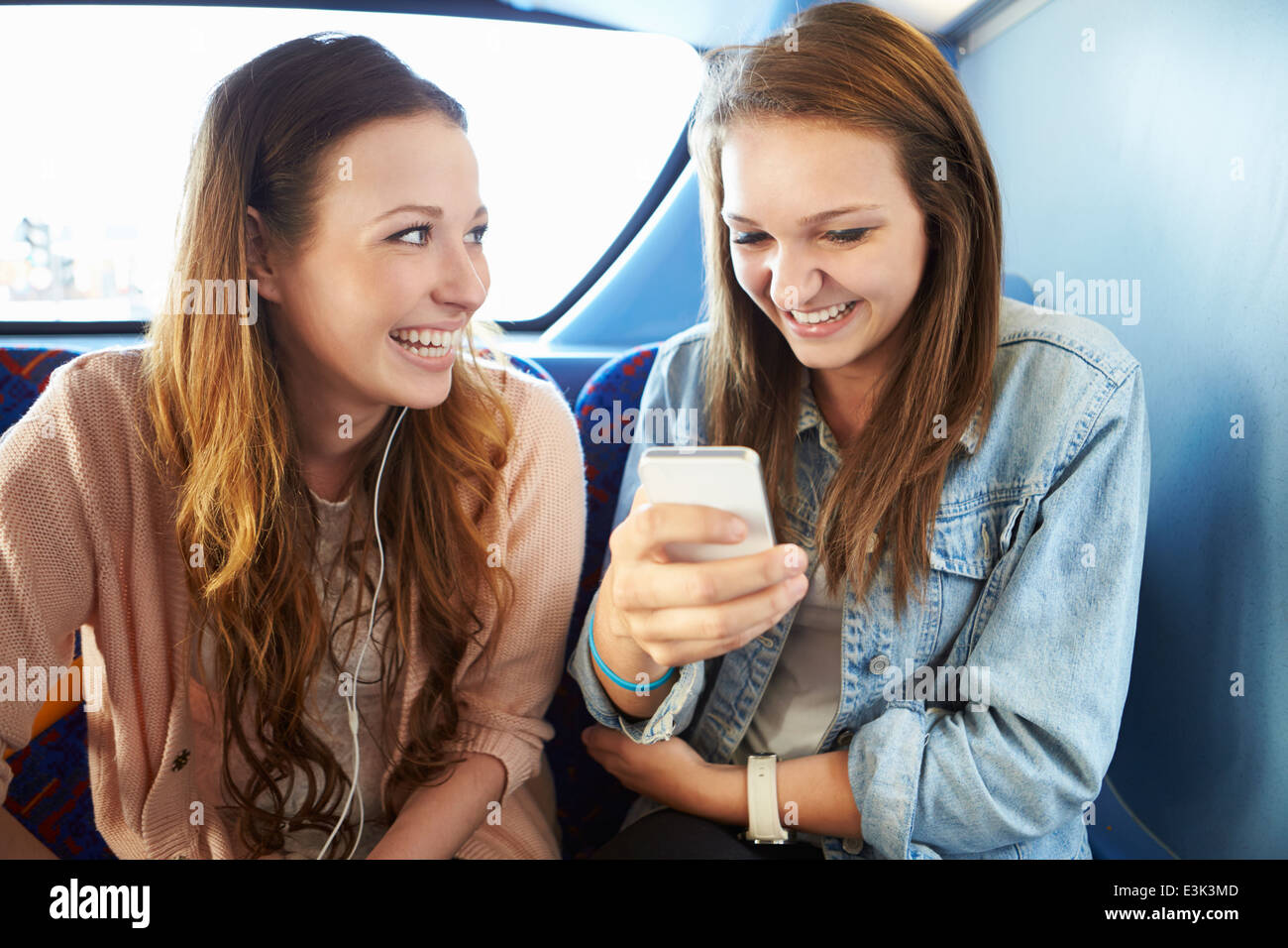 Two Young Women Reading Text Message On Bus Stock Photo - Alamy