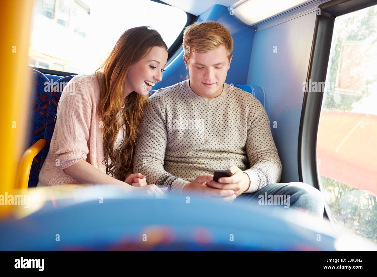 Teenage Couple Reading Text Message On Bus Stock Photo - Alamy