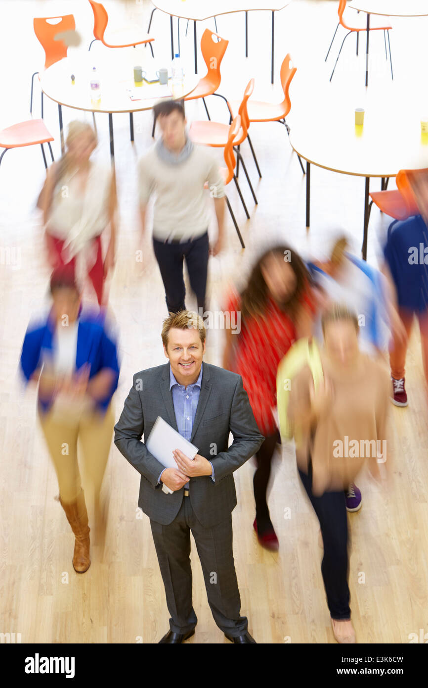 Male Tutor In Classroom Surrounded By Moving Students Stock Photo - Alamy