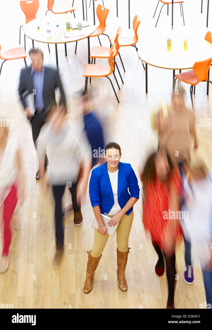 Female Tutor In Classroom Surrounded By Moving Students Stock Photo - Alamy