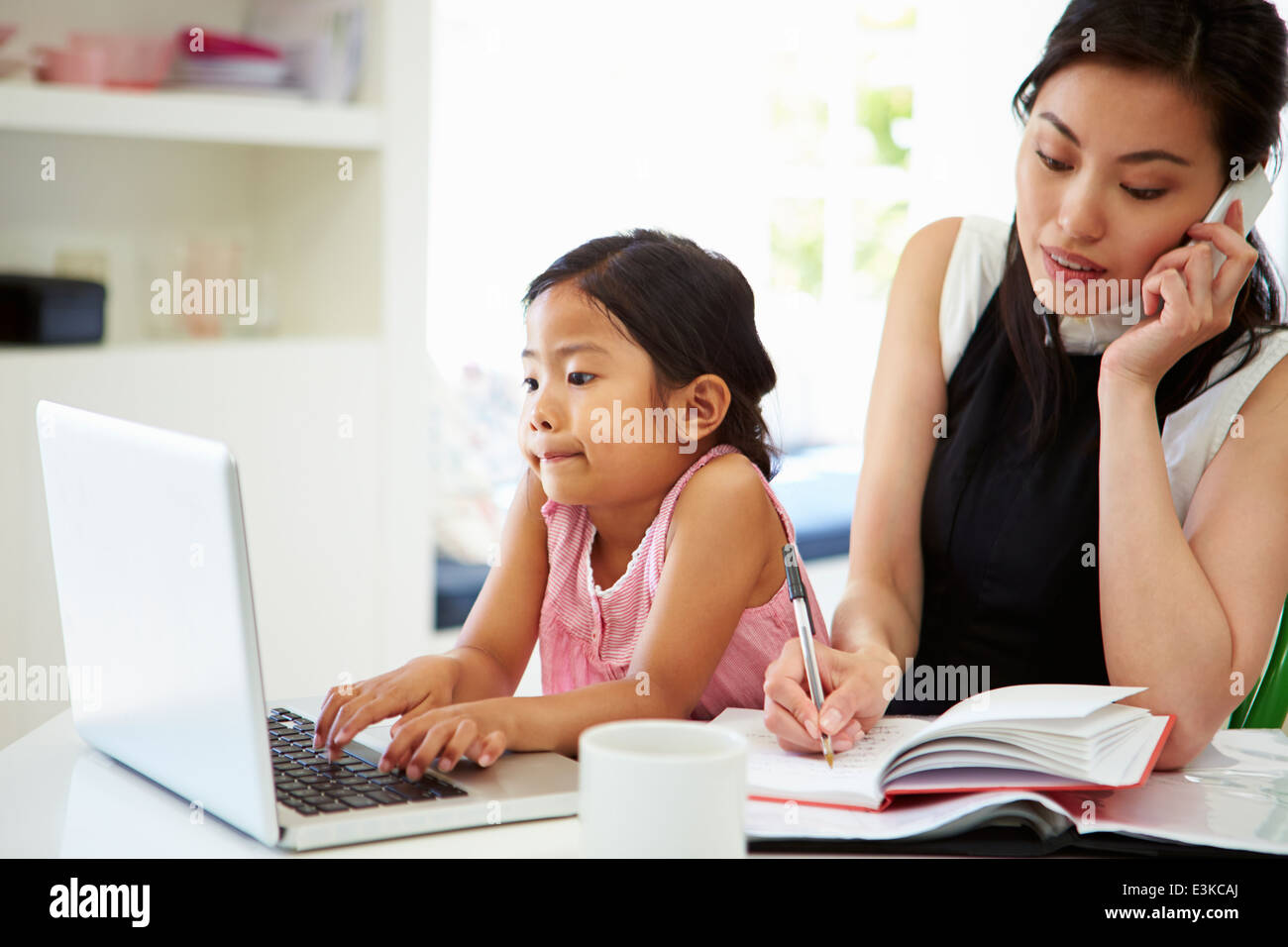 Busy Mother Working From Home With Daughter Stock Photo - Alamy