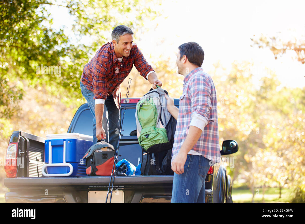 Two Men Unpacking Pick Up Truck On Camping Holiday Stock Photo - Alamy
