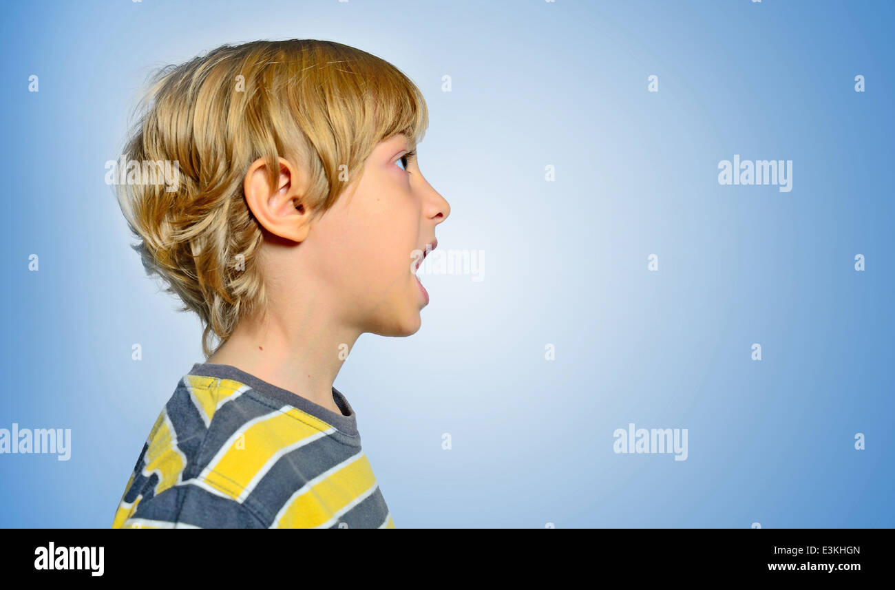 Amazed young boy on blue background Stock Photo - Alamy
