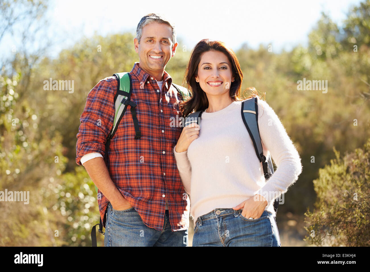 Portrait Of Couple Hiking In Countryside Wearing Backpacks Stock Photo ...