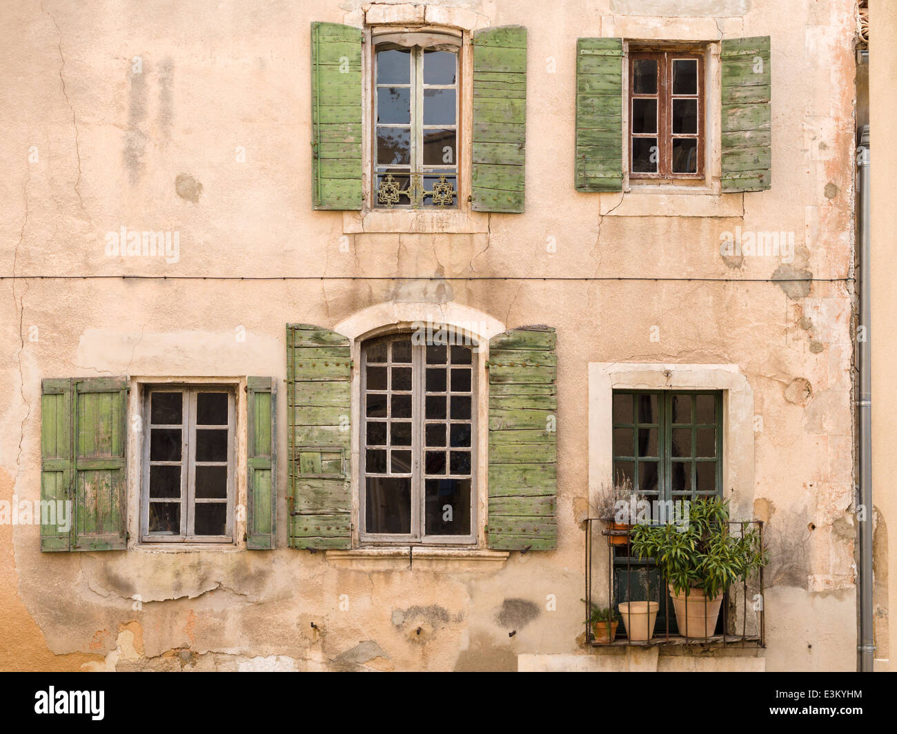 The wall of a house in a Provencal village. Windows, balcony and rough ...