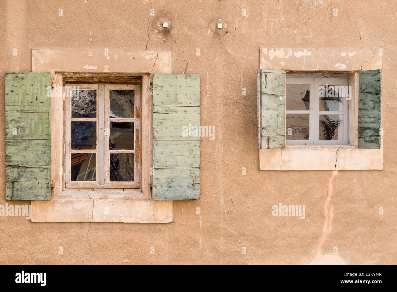 Green Shuttered windows. A pair of windows one small on a tan coloured ...