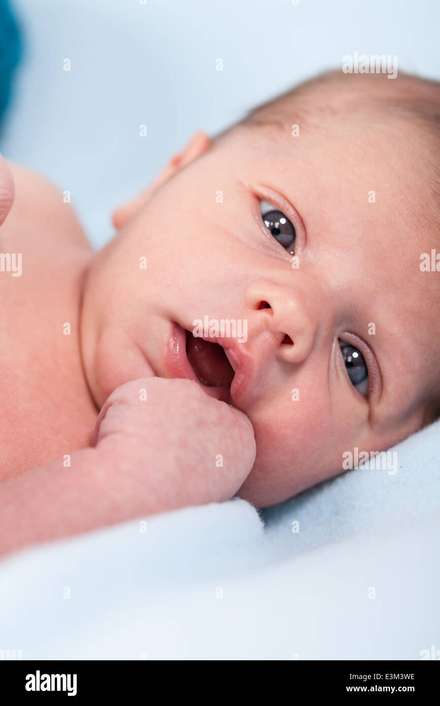 Small infant wrapped in knitted fabric lying on soft white bed Stock ...