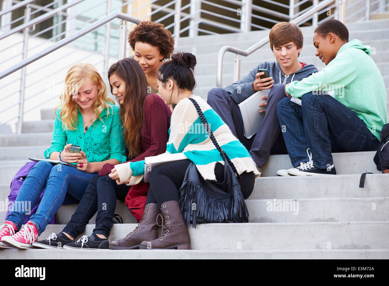 High School Students Sitting Outside Building With Phones Stock Photo ...