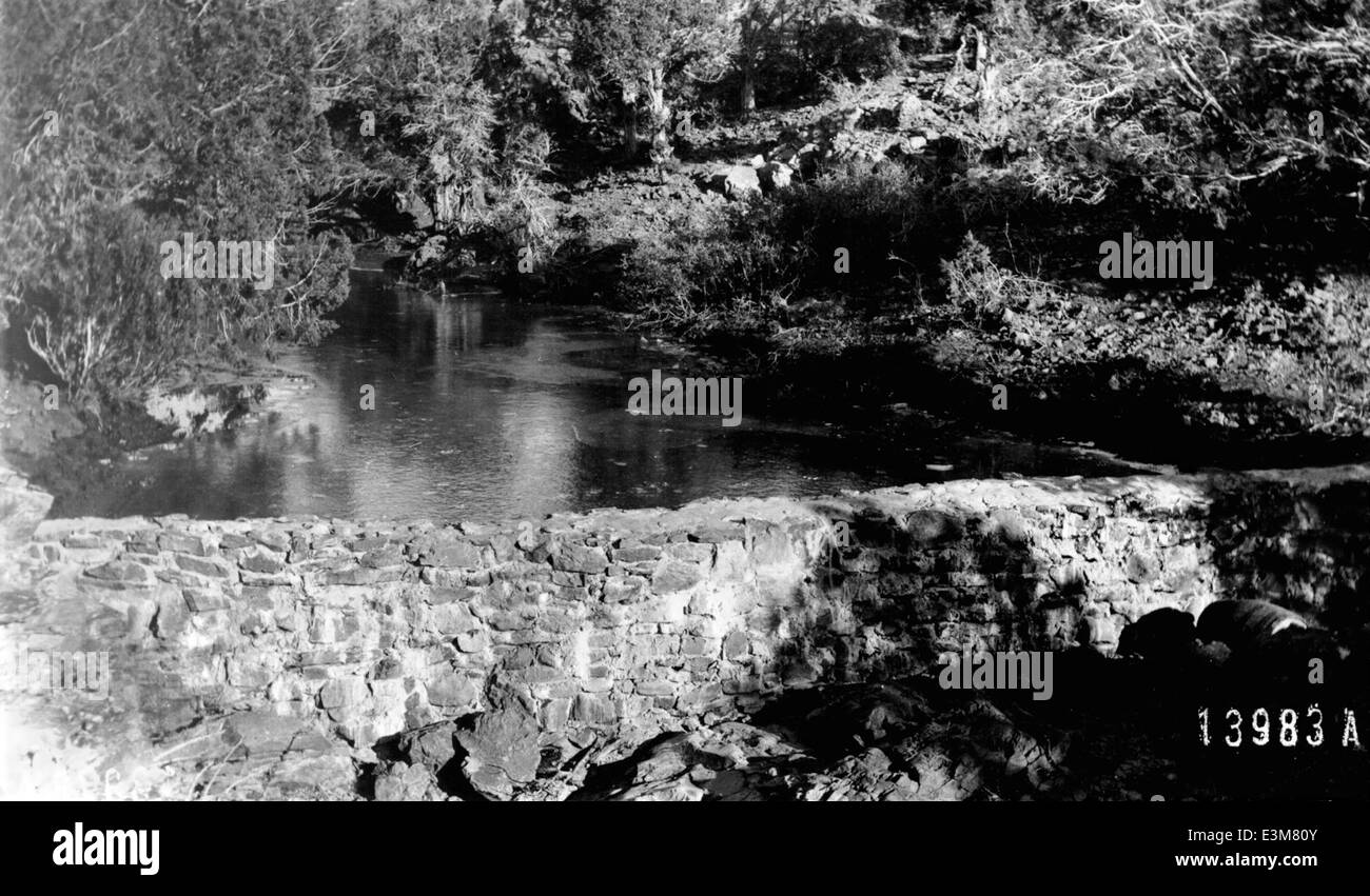 A historical photograph of a small masonry tank situated in a canyon ...