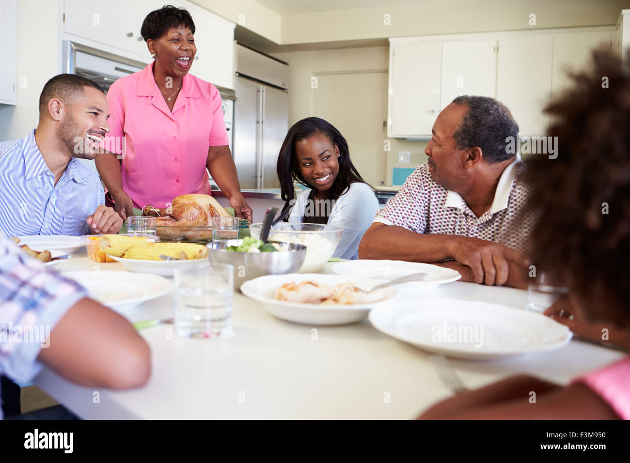 Multi-Generation Family Sitting Around Table Eating Meal Stock Photo ...