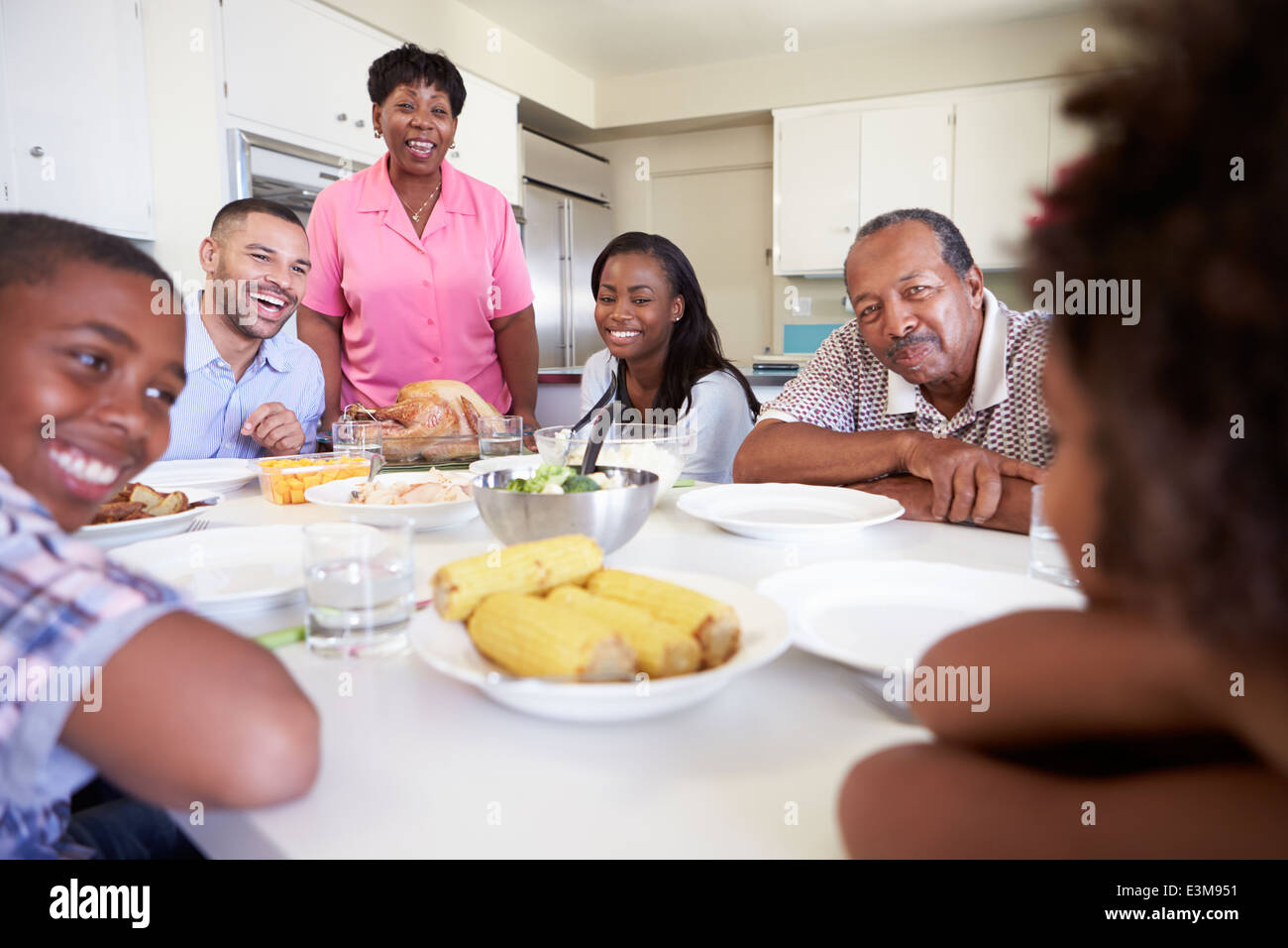 Multi-Generation Family Sitting Around Table Eating Meal Stock Photo ...